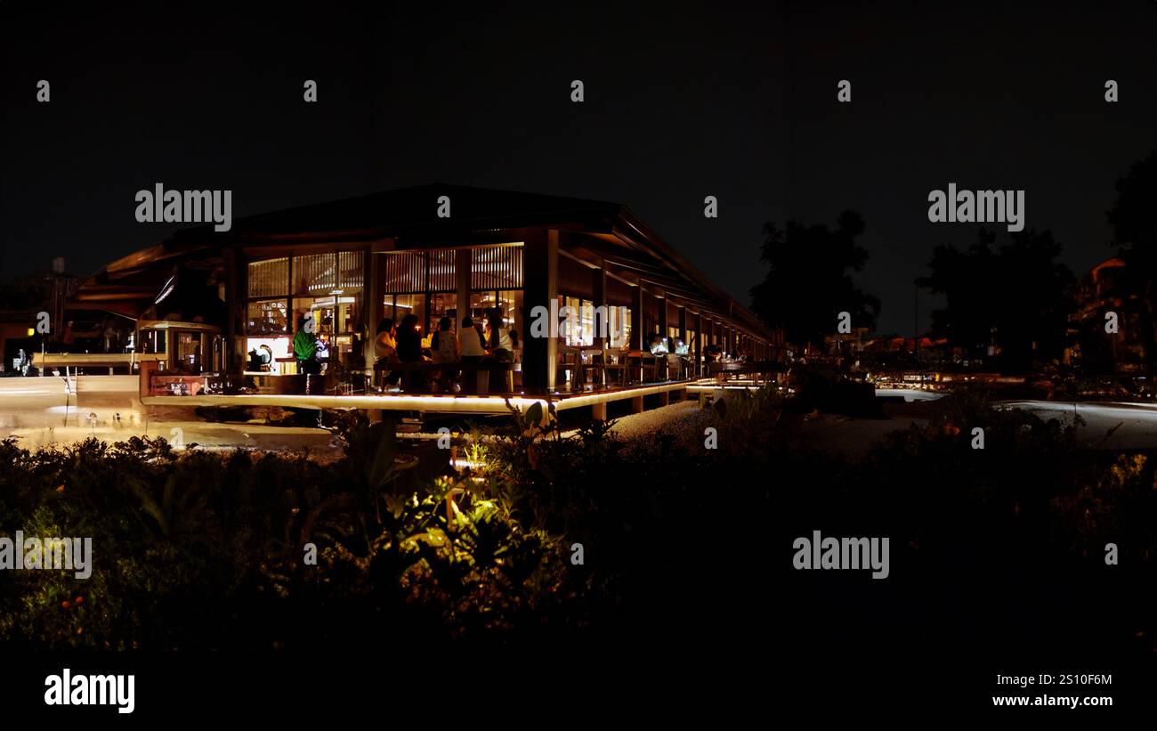 Modern restaurant with illuminated facade at night, surrounded by ...