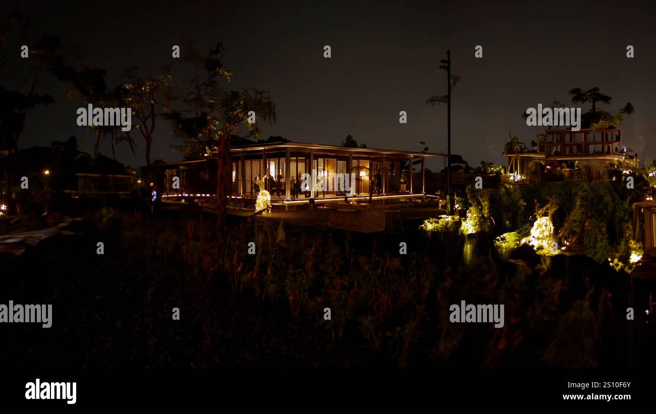 Tropical resort at night with illuminated bungalow and palm trees in ...