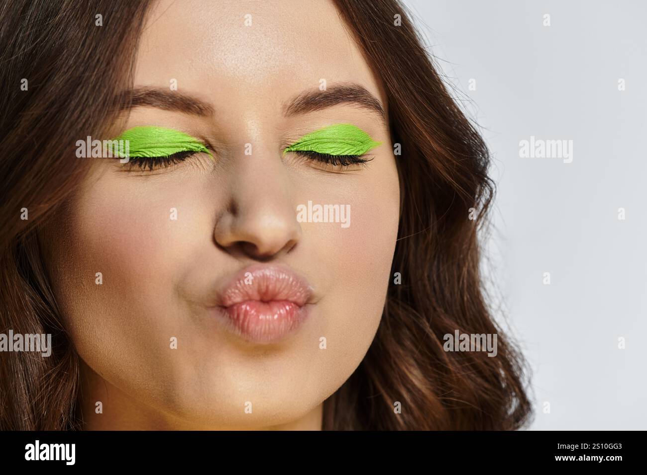 Vibrant green eyeshadow highlights her beauty, while playful expression ...