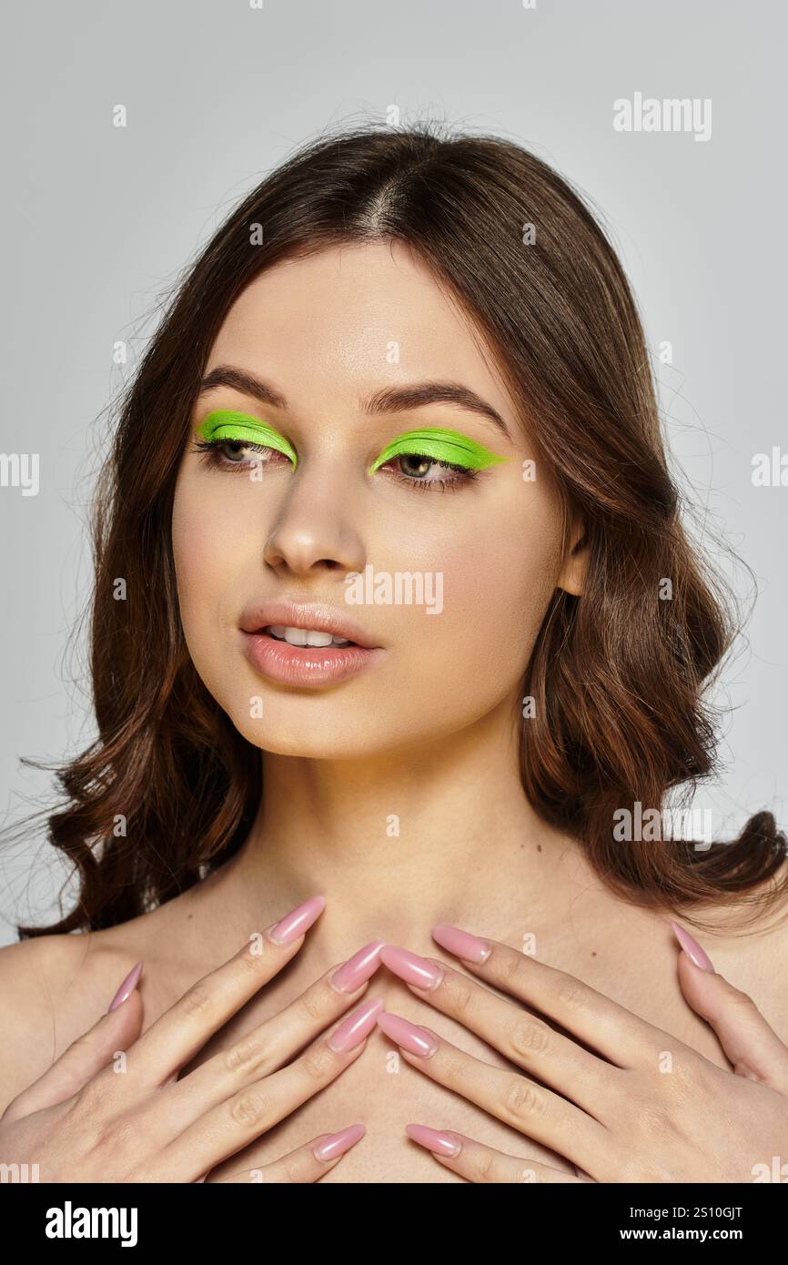 A young woman displays her striking beauty with bold green eyeshadow ...