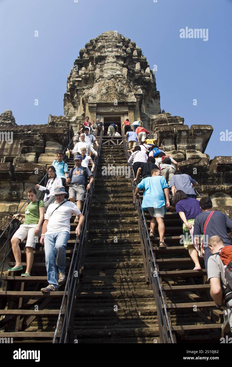 Tourists climb steep stairs at the Angkor Wat temple complex, Cambodia ...