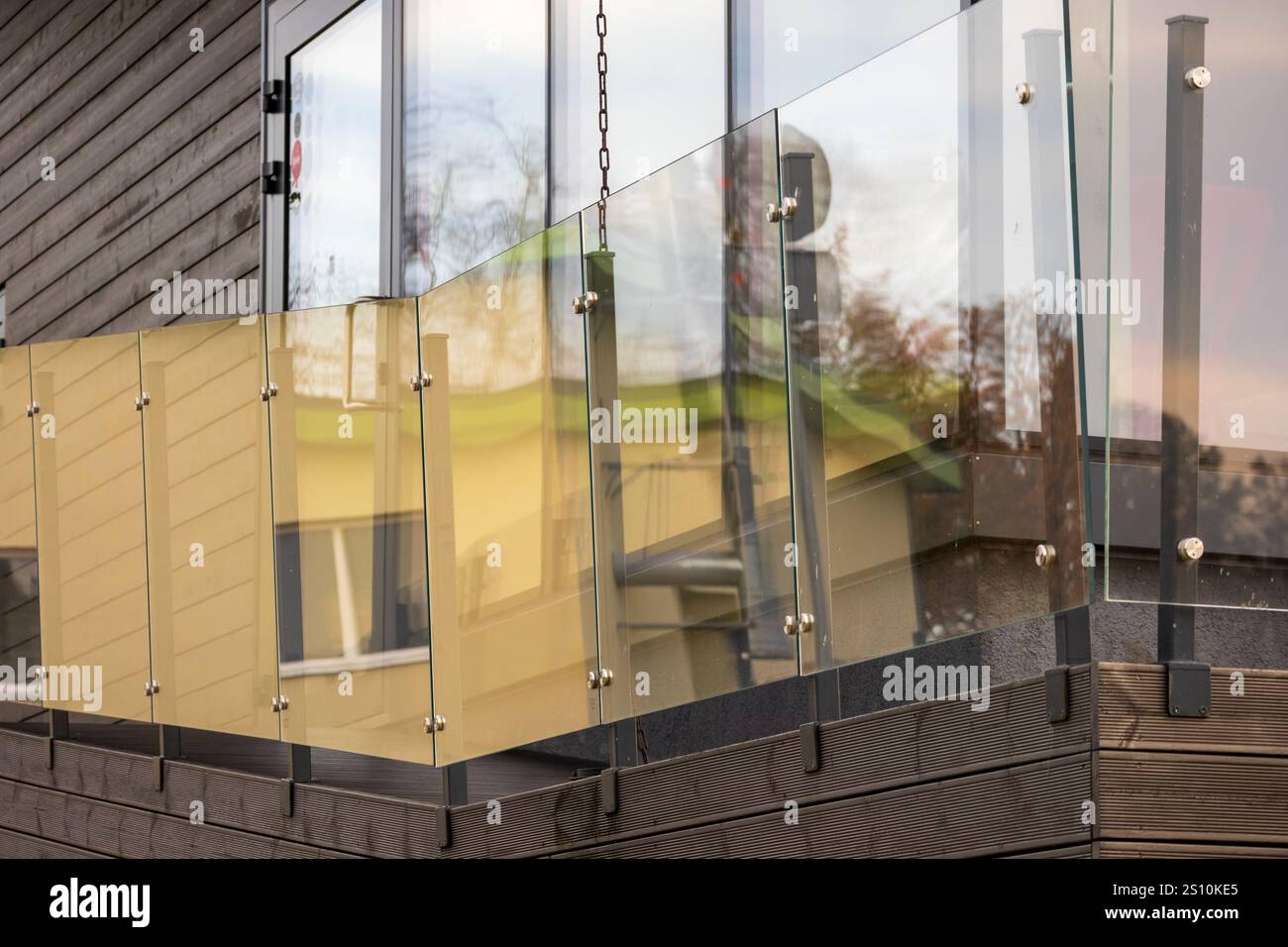 Balcony enclosed by glass balcony railings. The floor of the balcony is ...