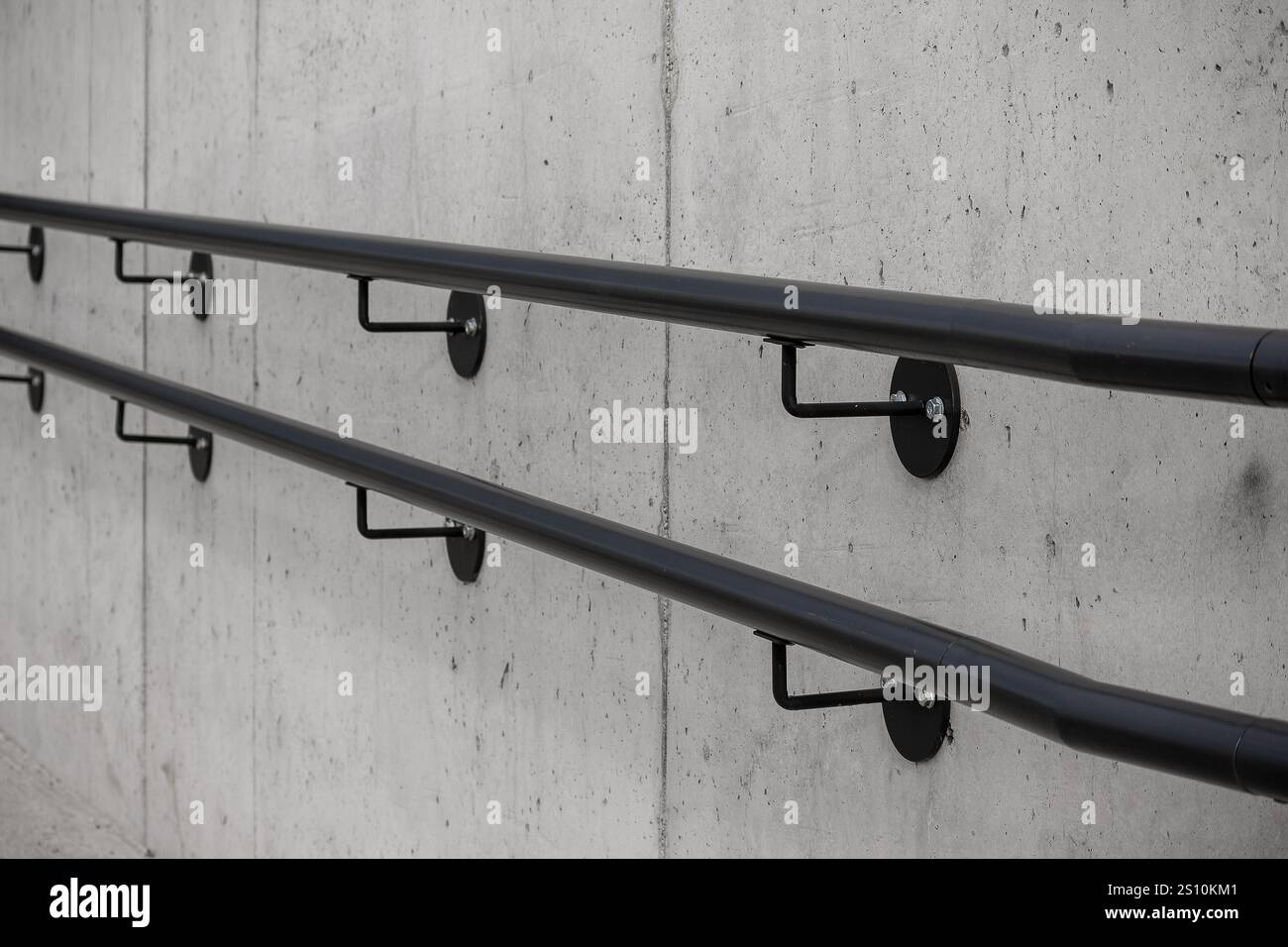 A fragment of a concrete wall with attached metal railings. The ...