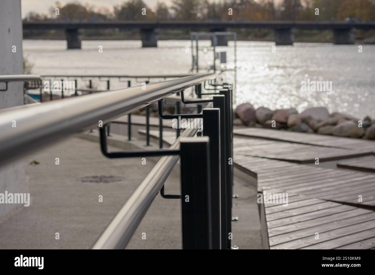 River bank with concrete promenade and metal railings. A bridge over ...