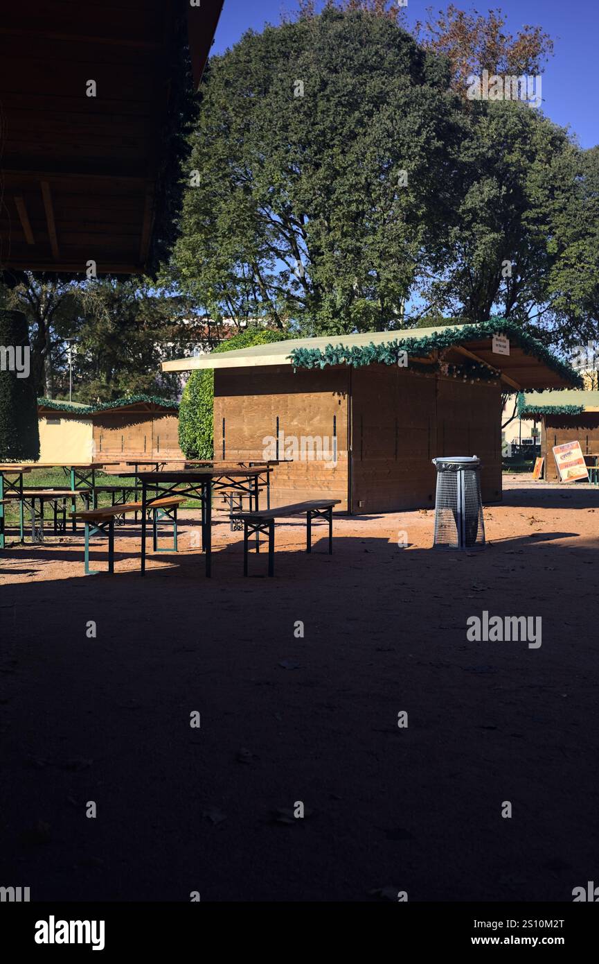 Closed huts of a Christmas market and empty tables near them during ...