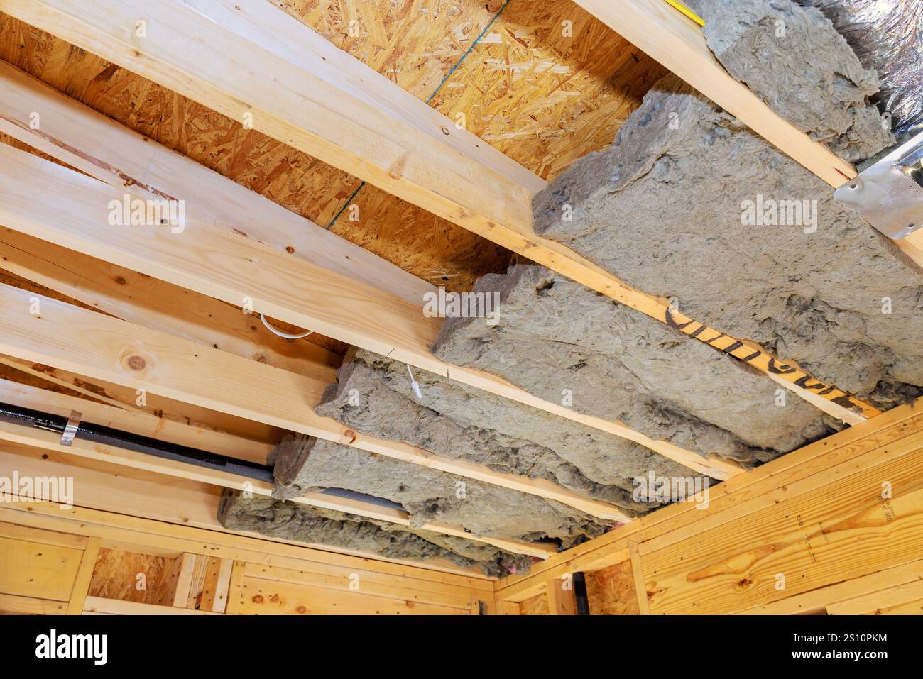 Laying insulation between wooden beams during construction new home at ...