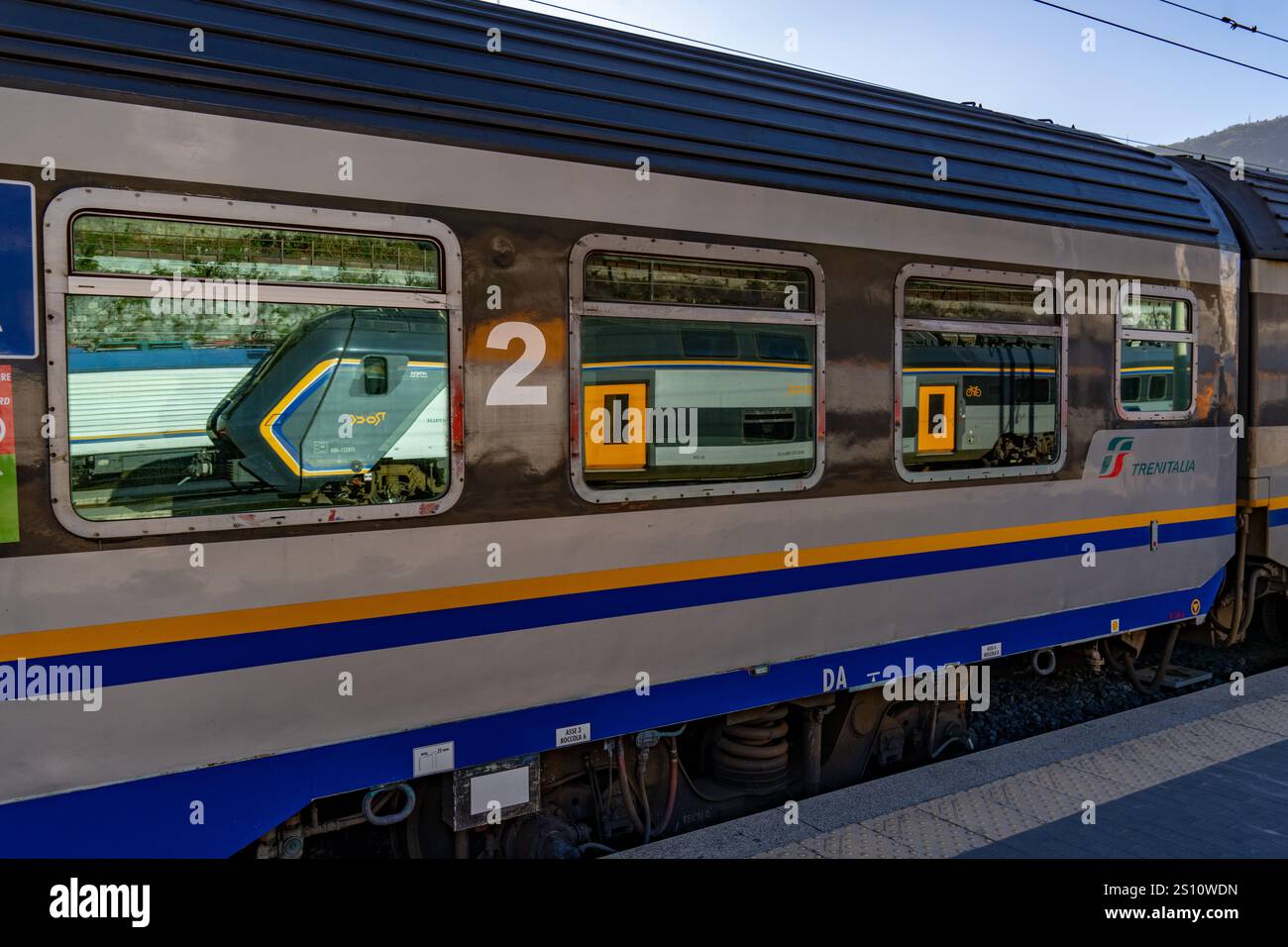 A Trenitalia Rock train reflected in the windows of a Pop regional passenger train in La Spezia ...