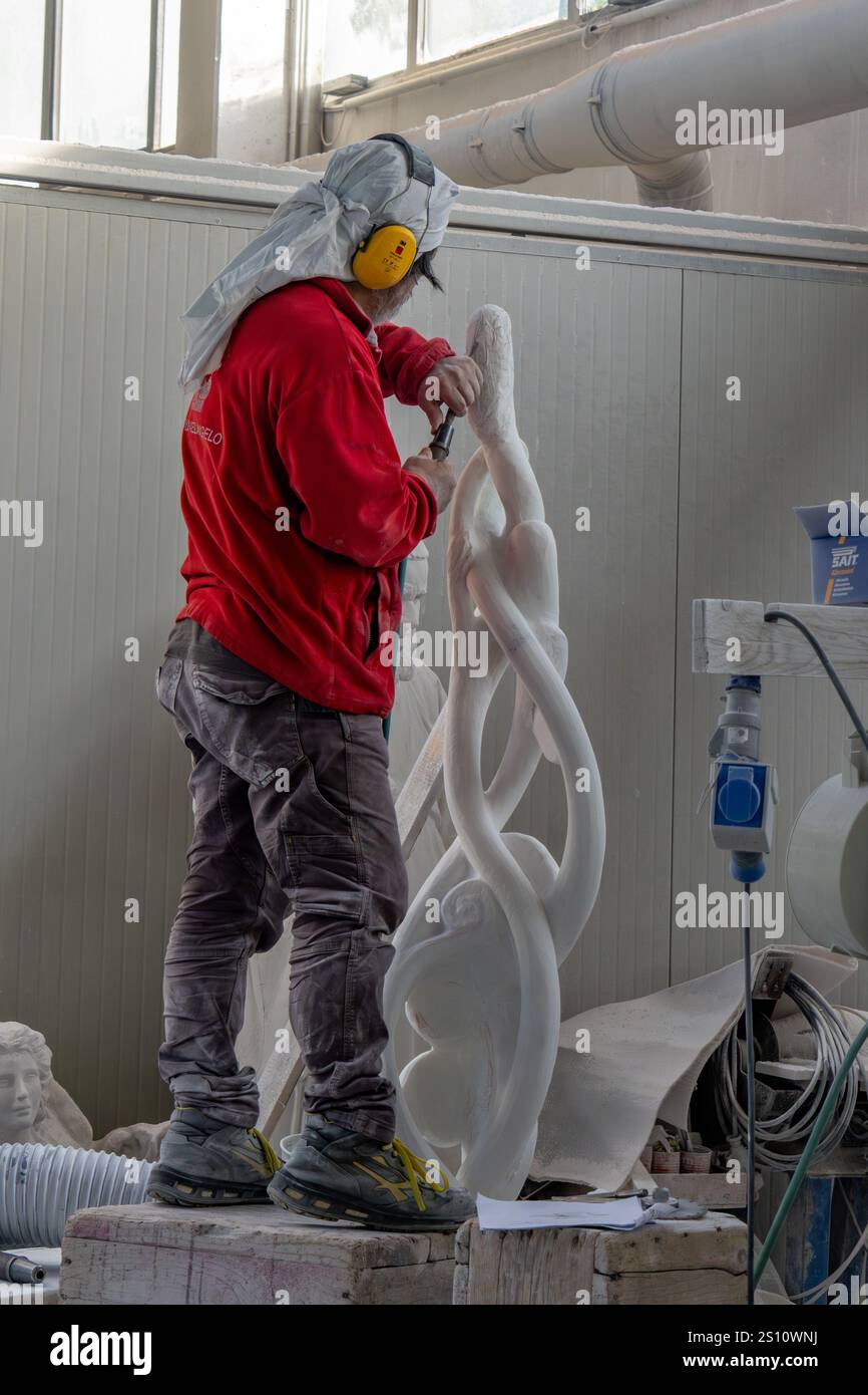 A sculptor uses a pneumatic chisel to carve a marble statue in a ...