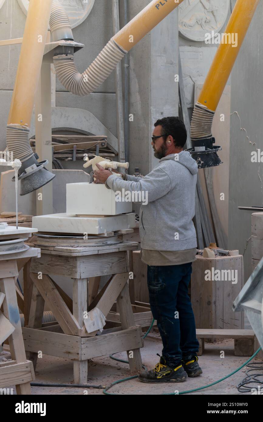 A sculptor makes reference marks on a block of marble in a marble ...