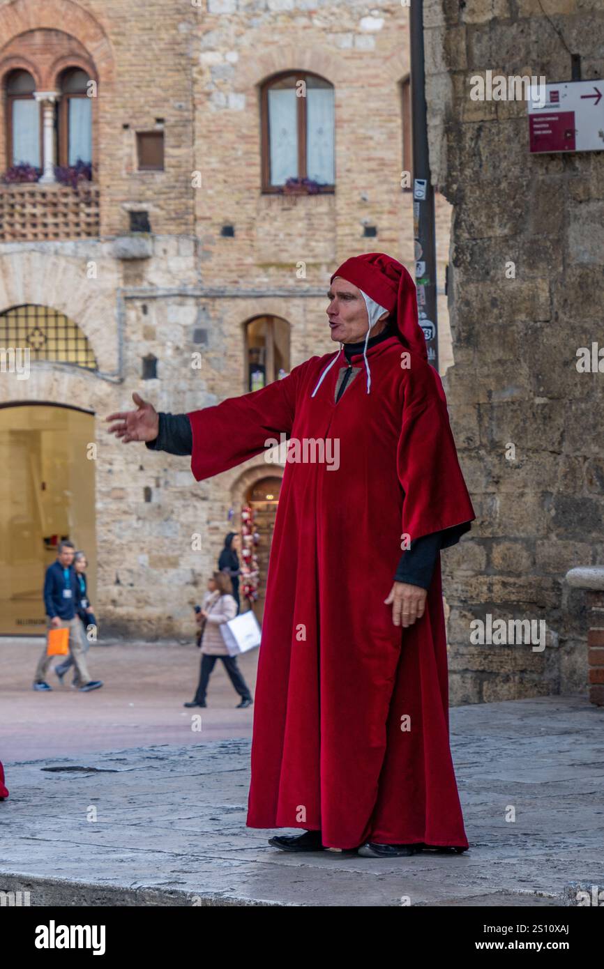 An actor in costume imitates Dante on the street in the medieval walled ...