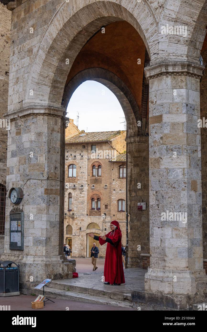 An actor in costume imitates Dante on the street in the medieval walled ...