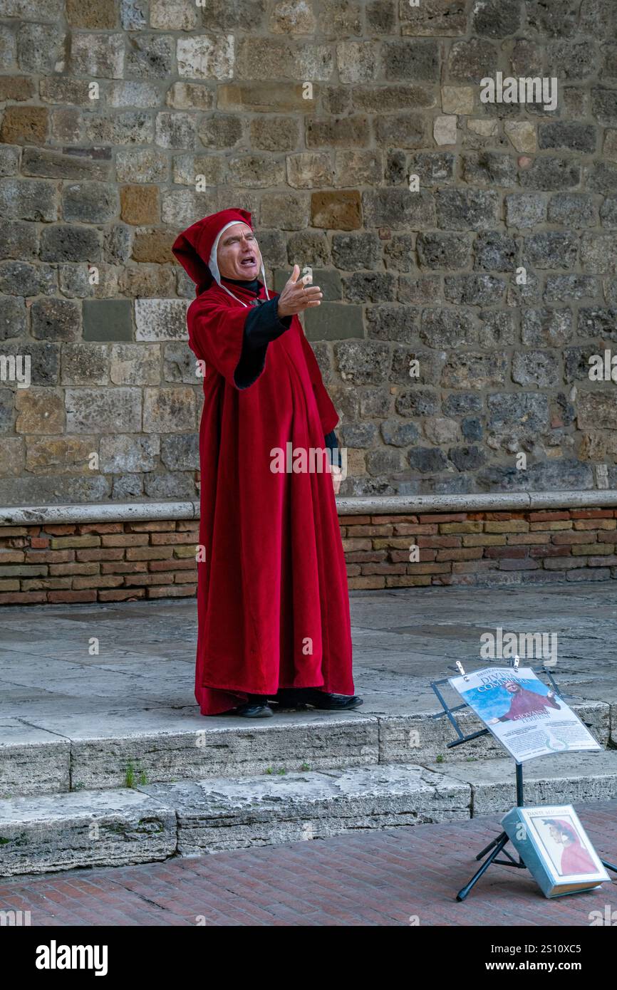An actor in costume imitates Dante on the street in the medieval walled ...