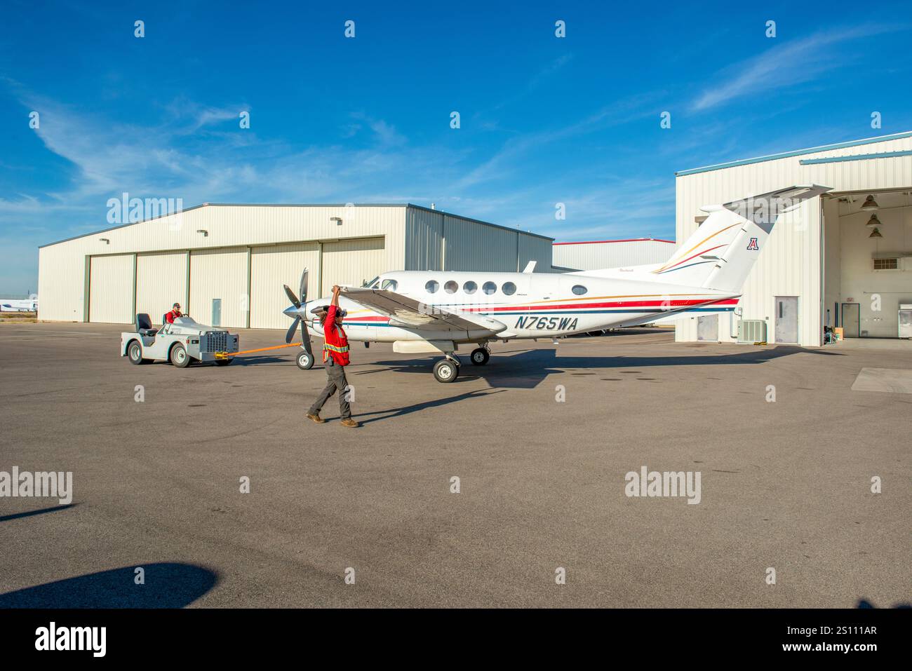 Tug driver pushing a plane to its parking spot with two other men ...