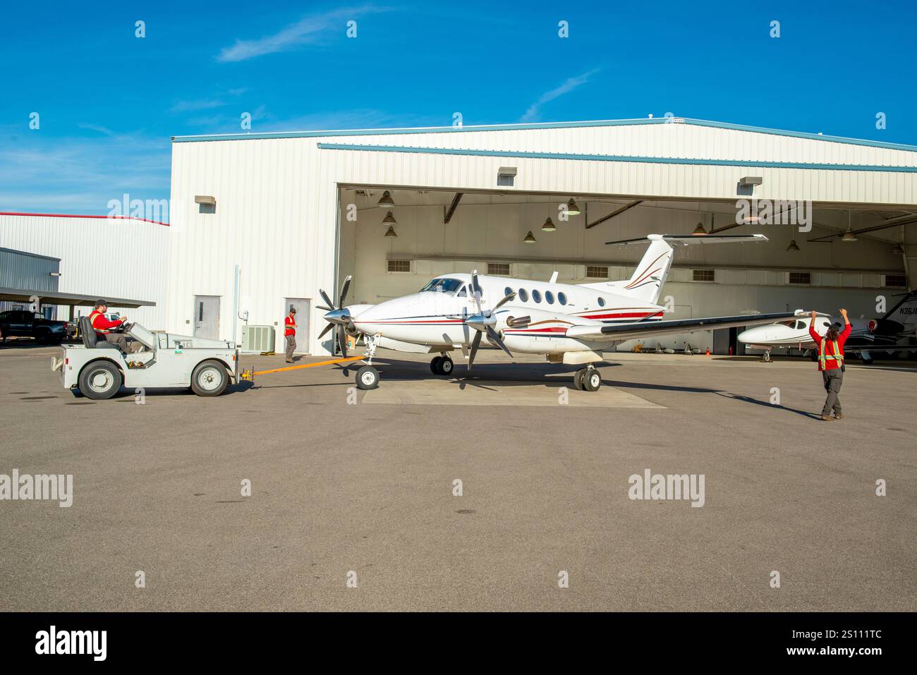 Tug driver pushing a plane to its parking spot with two other men ...