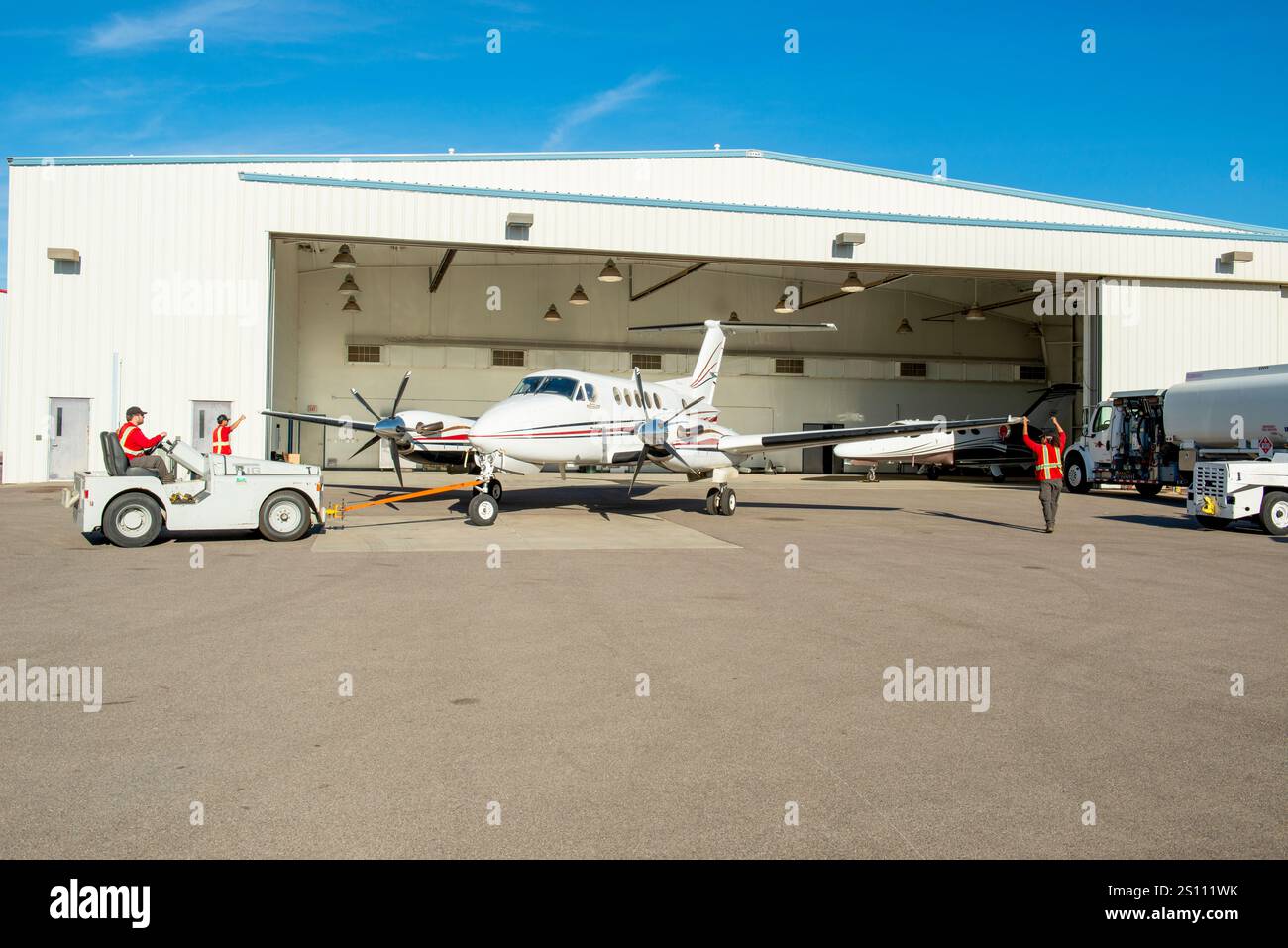 Tug driver pushing a plane to its parking spot with two other men ...