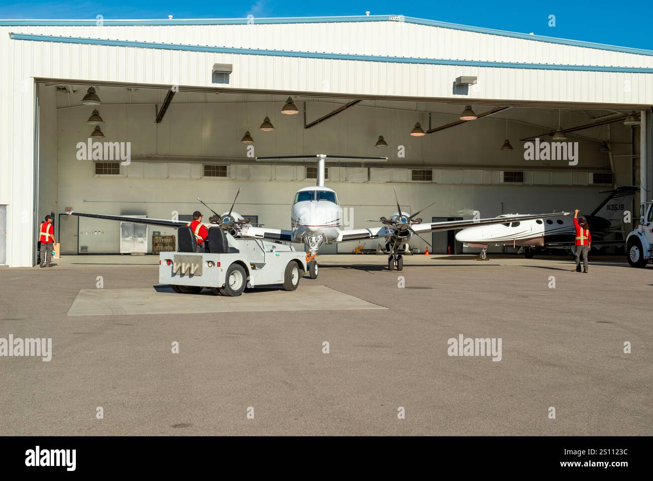 Tug driver pushing a plane to its parking spot with two other men ...