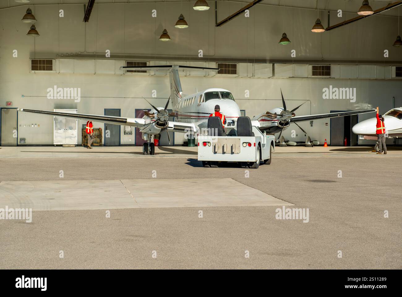 Tug driver pushing a plane to its parking spot with two other men ...