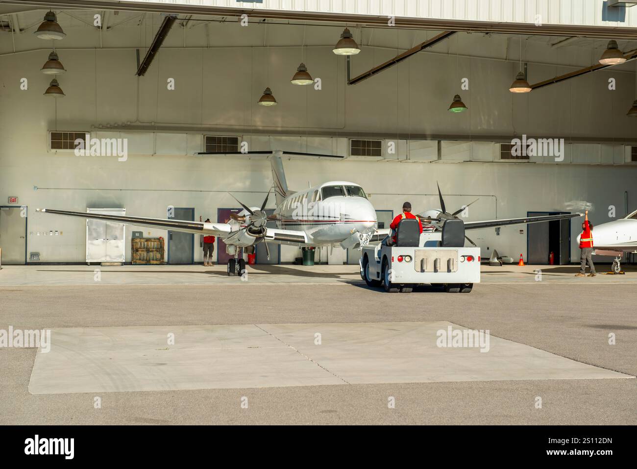 Tug driver pushing a plane to its parking spot with two other men ...