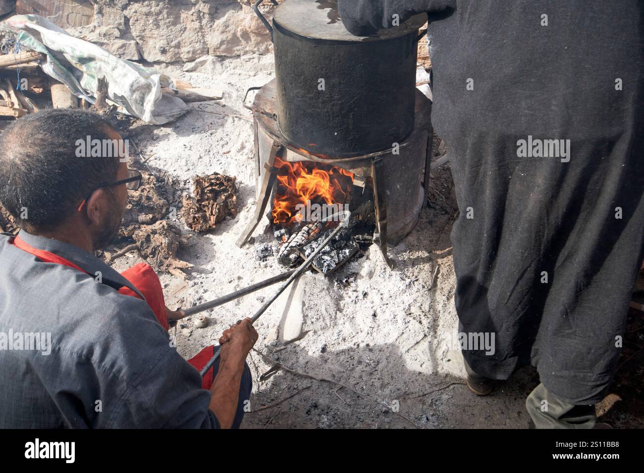 stoking wood fire boiling pot of soup or stew at traditional berber ...