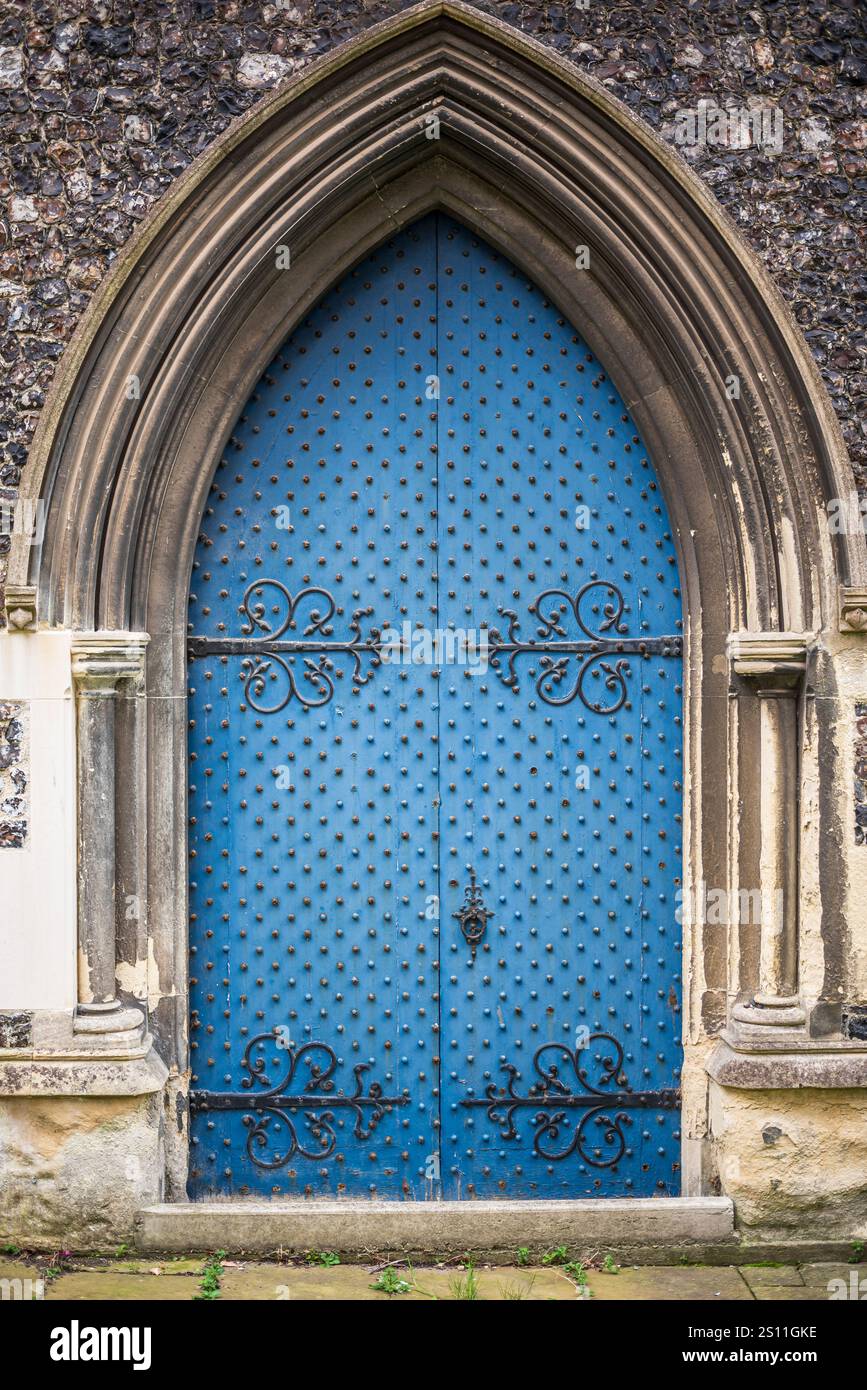 a blue wooden door in a gothic arch of a church with flintstone facade ...