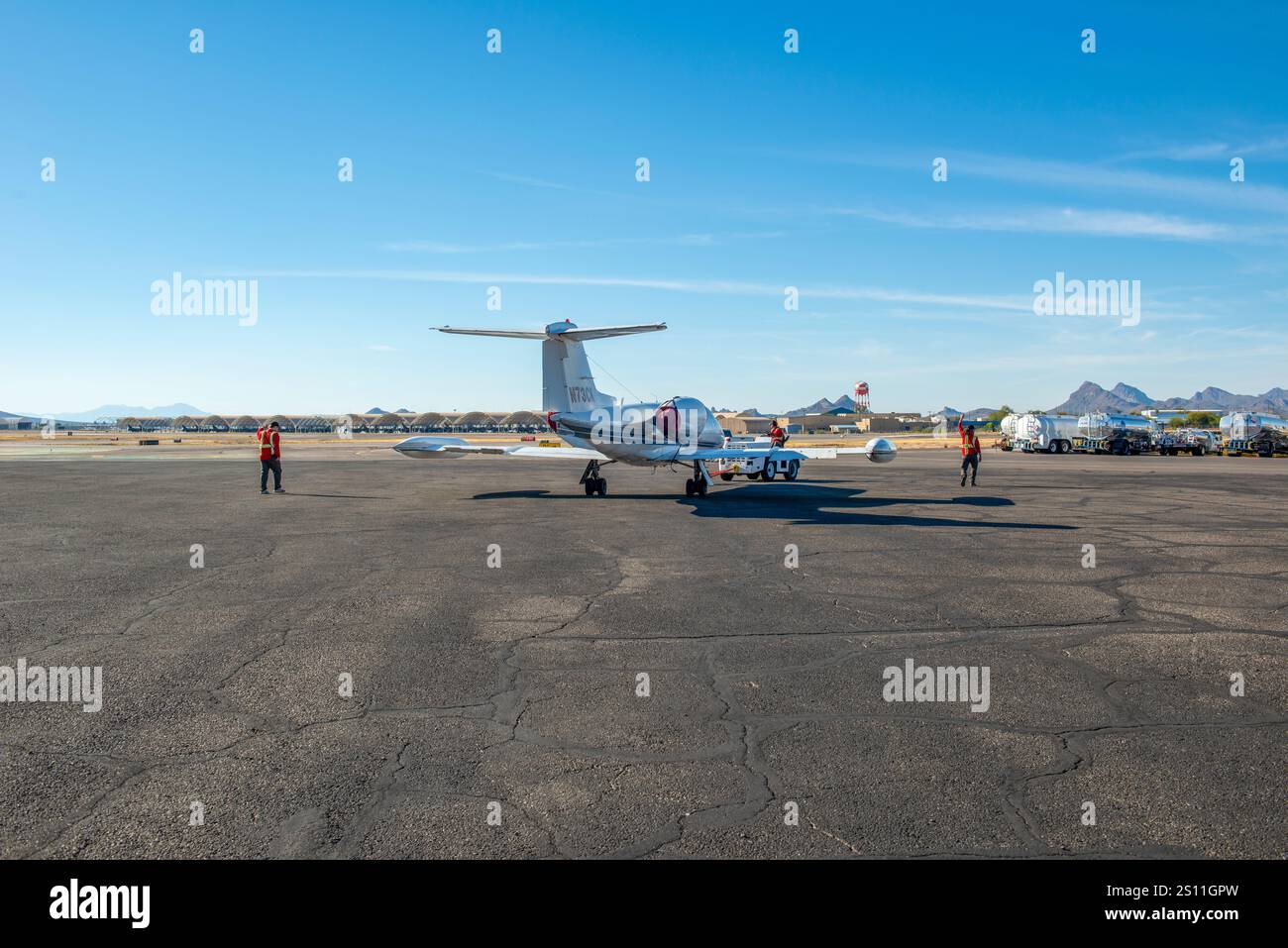Tug driver pushing a plane to its parking spot with two other men ...