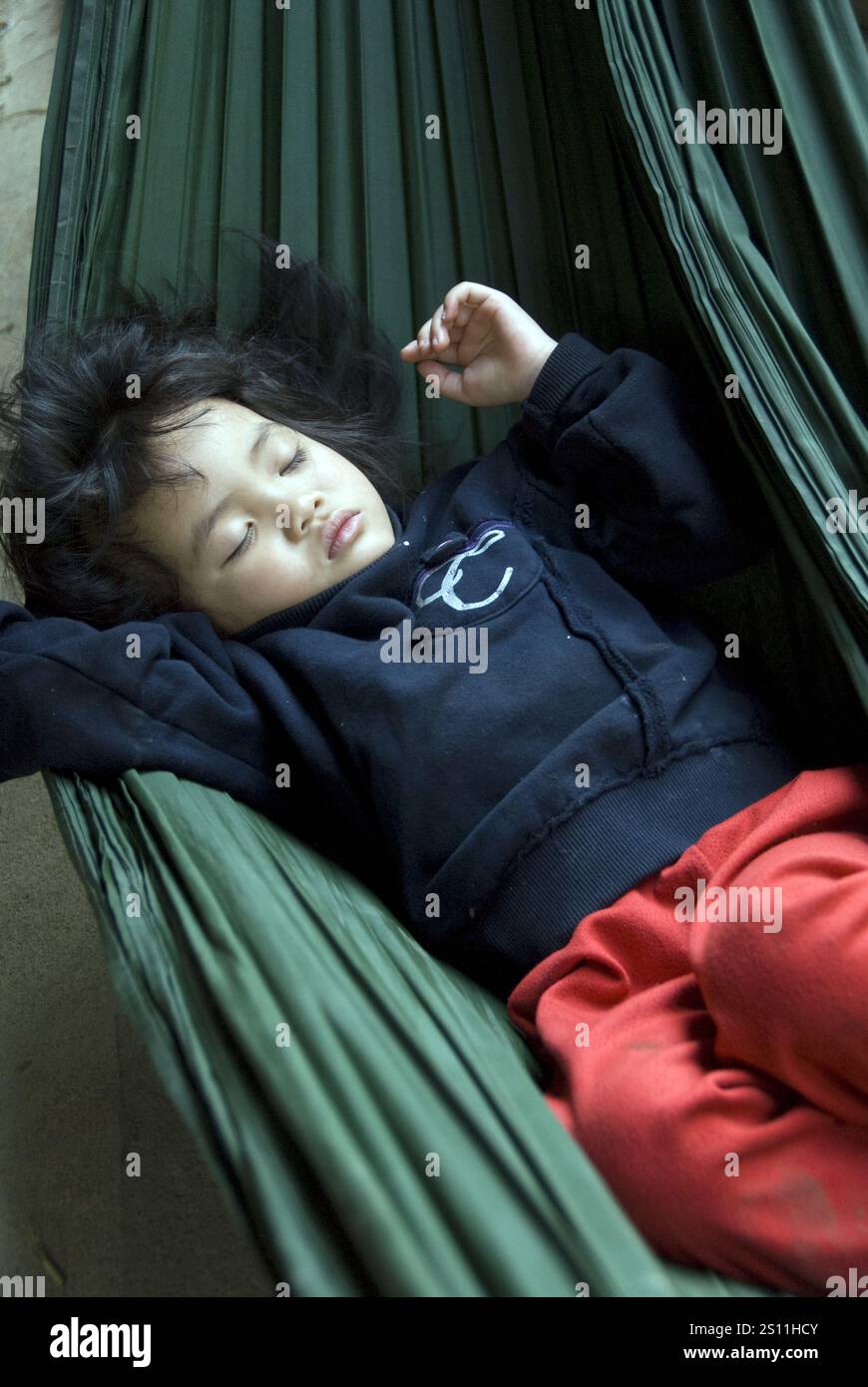 A child sleeps in hammock beneath the Khor Sang House, a traditional ...