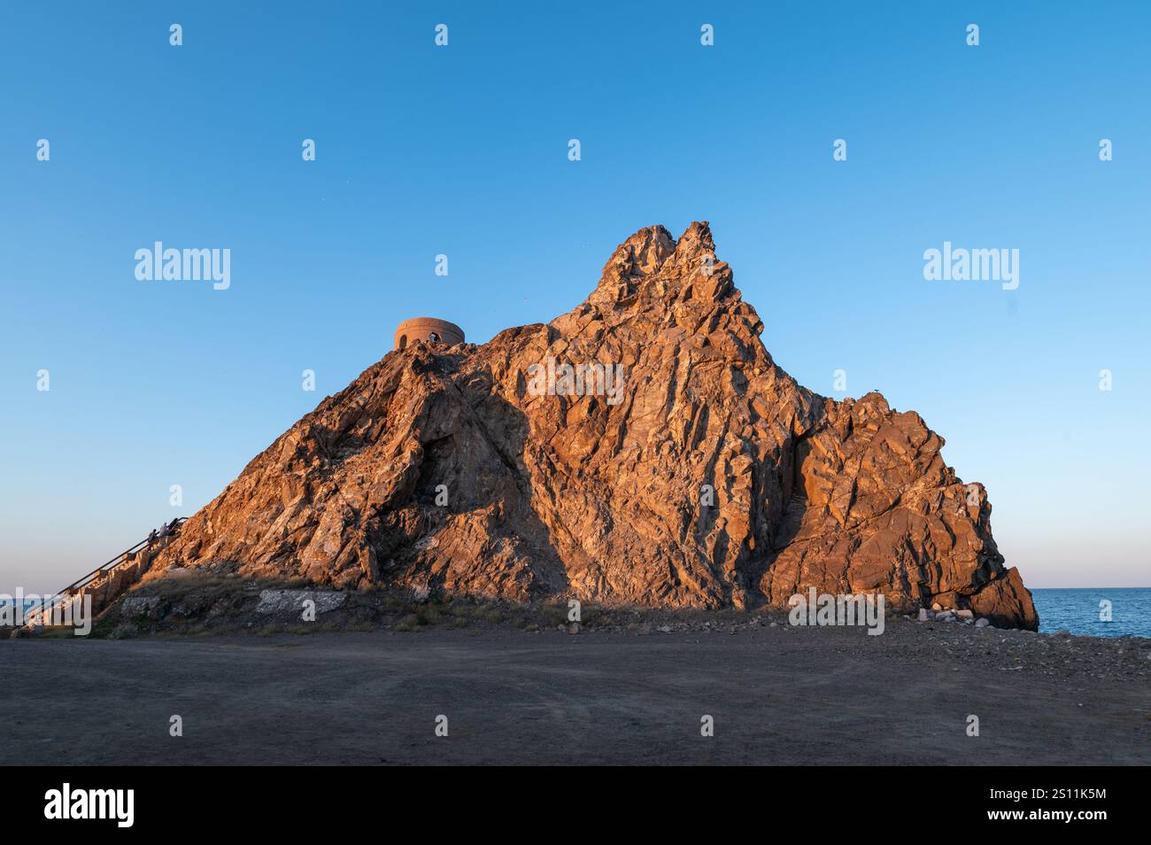Muscat Marine Tower perched atop a rugged rocky outcrop, illuminated by ...