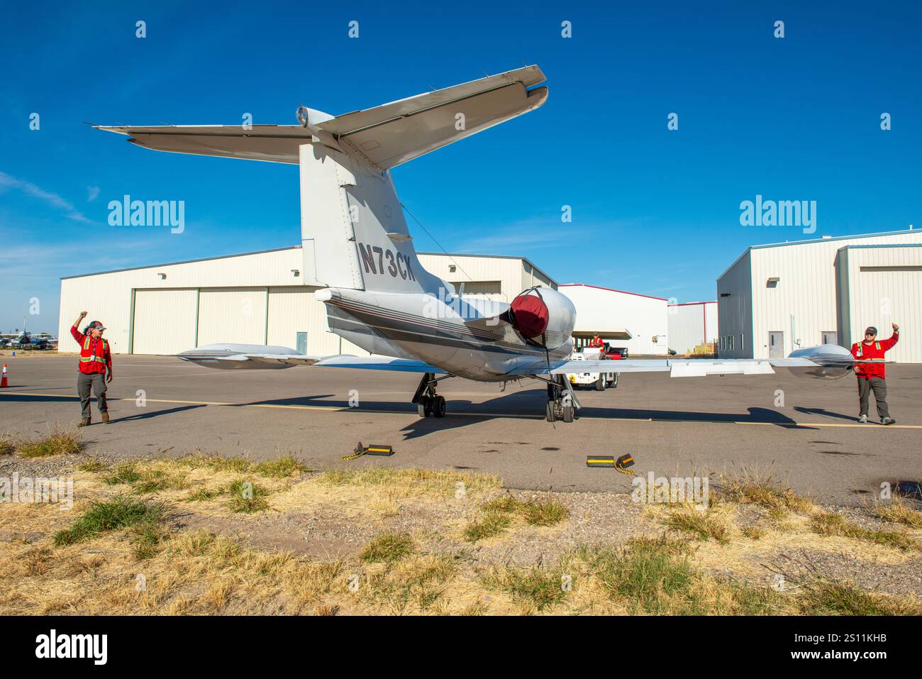 Tug driver pushing a plane to its parking spot with two other men ...