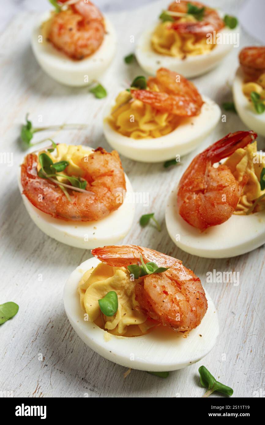 Boiled eggs stuffed with yolk and seasoned with mayonnaise, stuffed eggs with shrimp, on a white ...