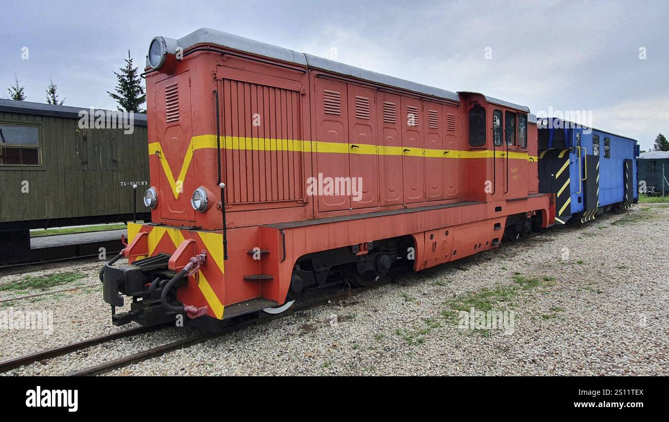 Red and yellow diesel locomotive on narrow-gauge tracks in the open air ...