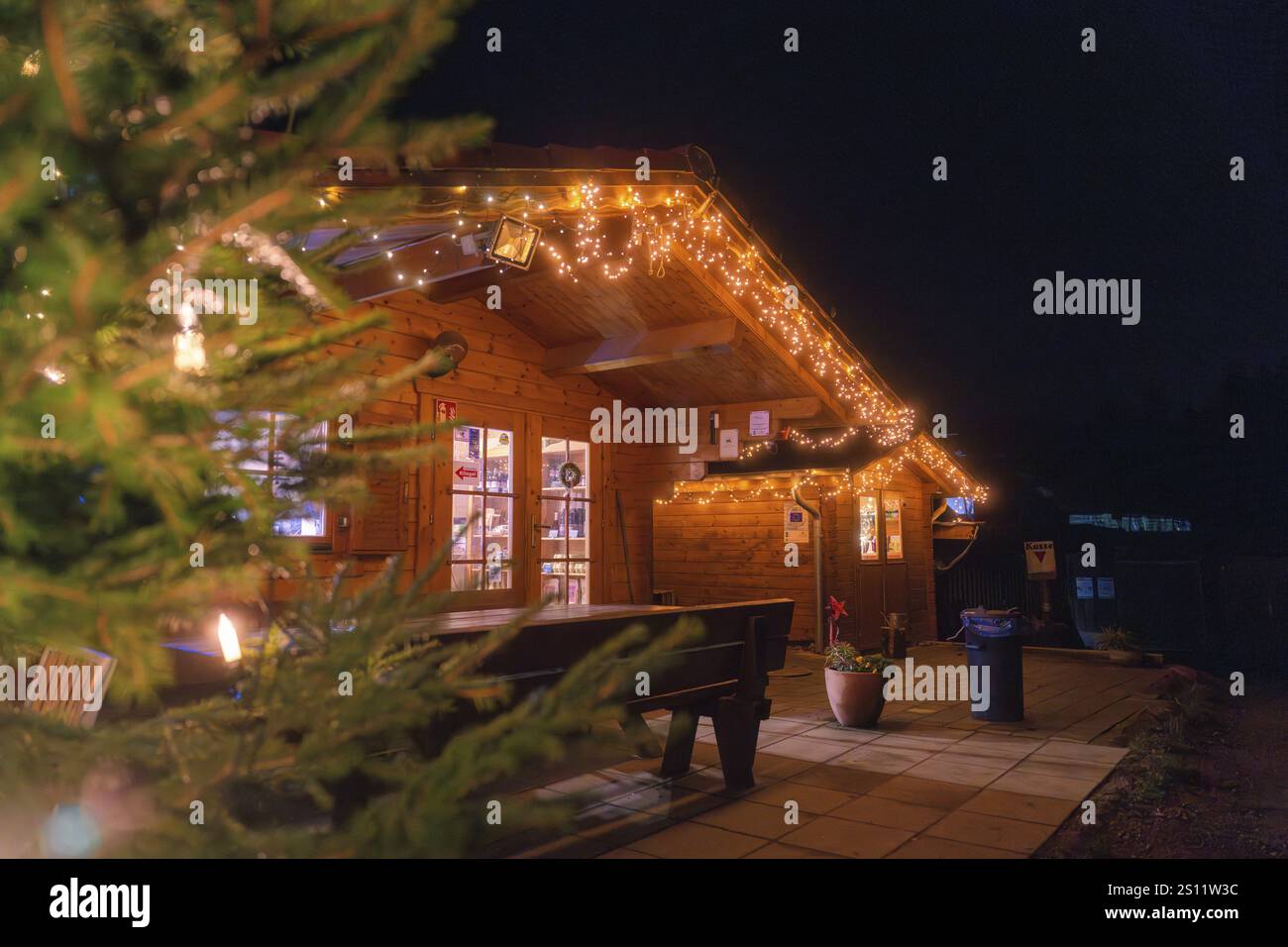 Atmospherically illuminated wooden hut at night with terrace and ...