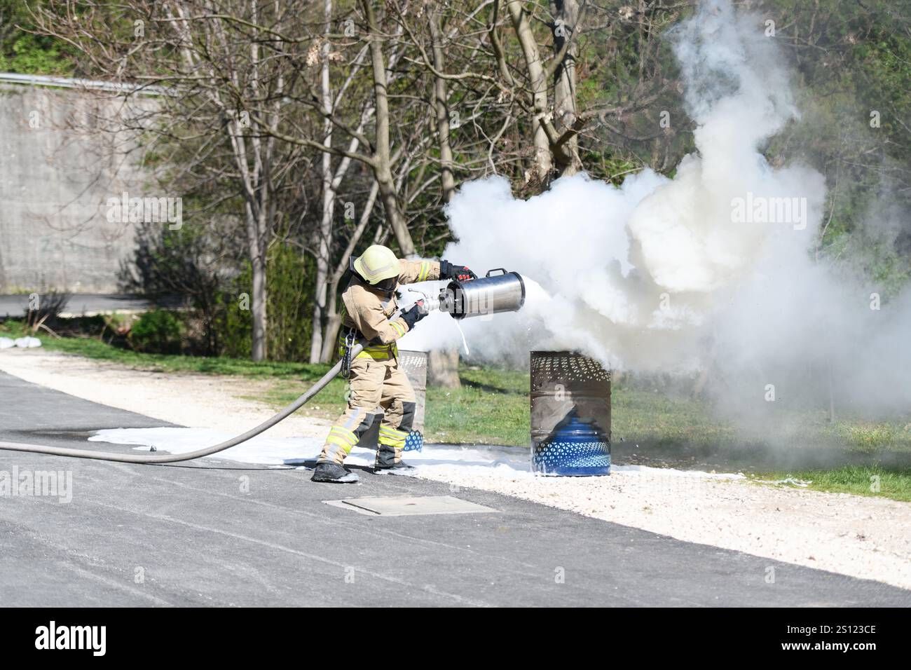 Firefighter using foam to extinguish fire on a melted oil can in a ...