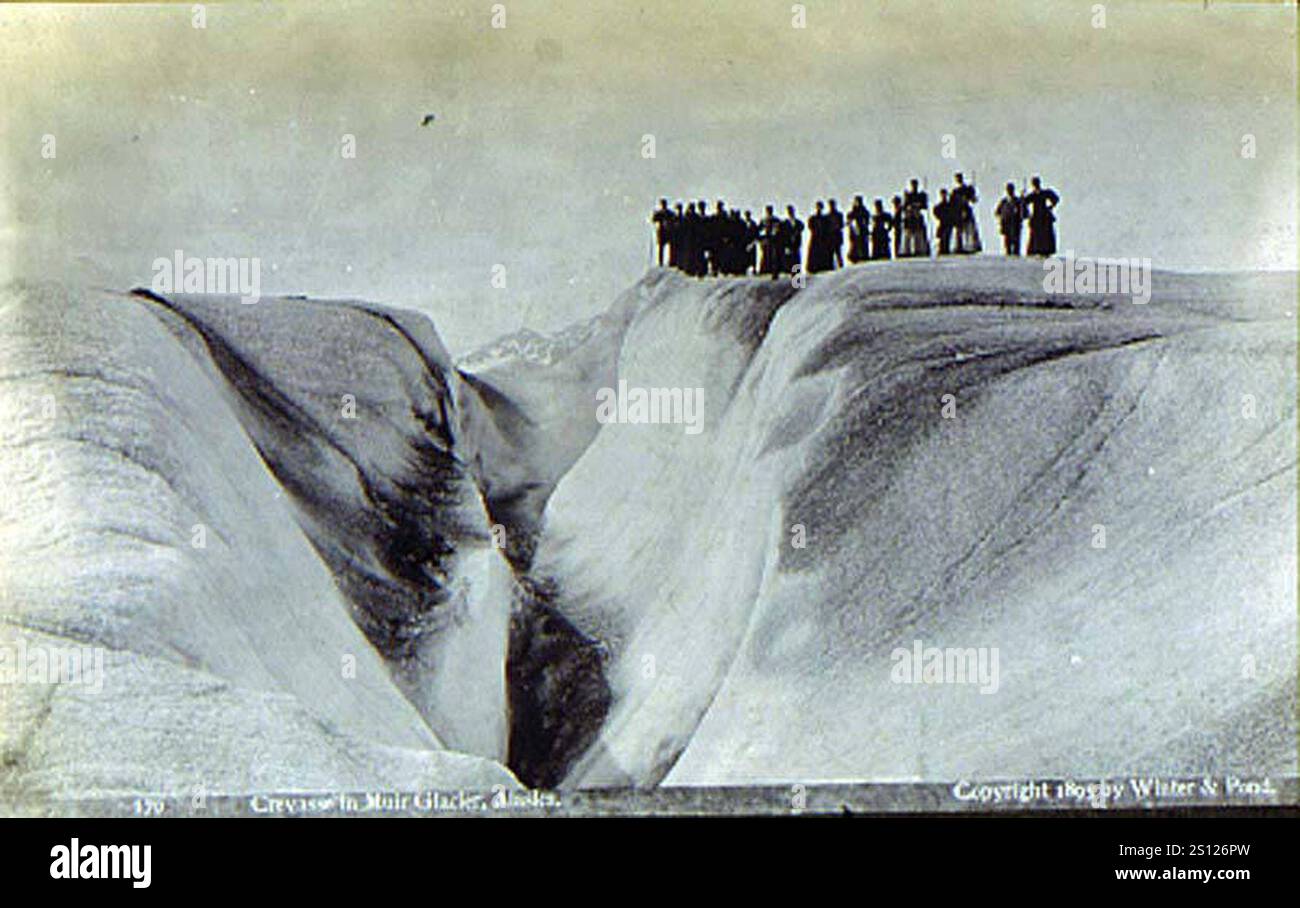 Excursion party posing at the edge of a crevasse in Muir Glacier ...