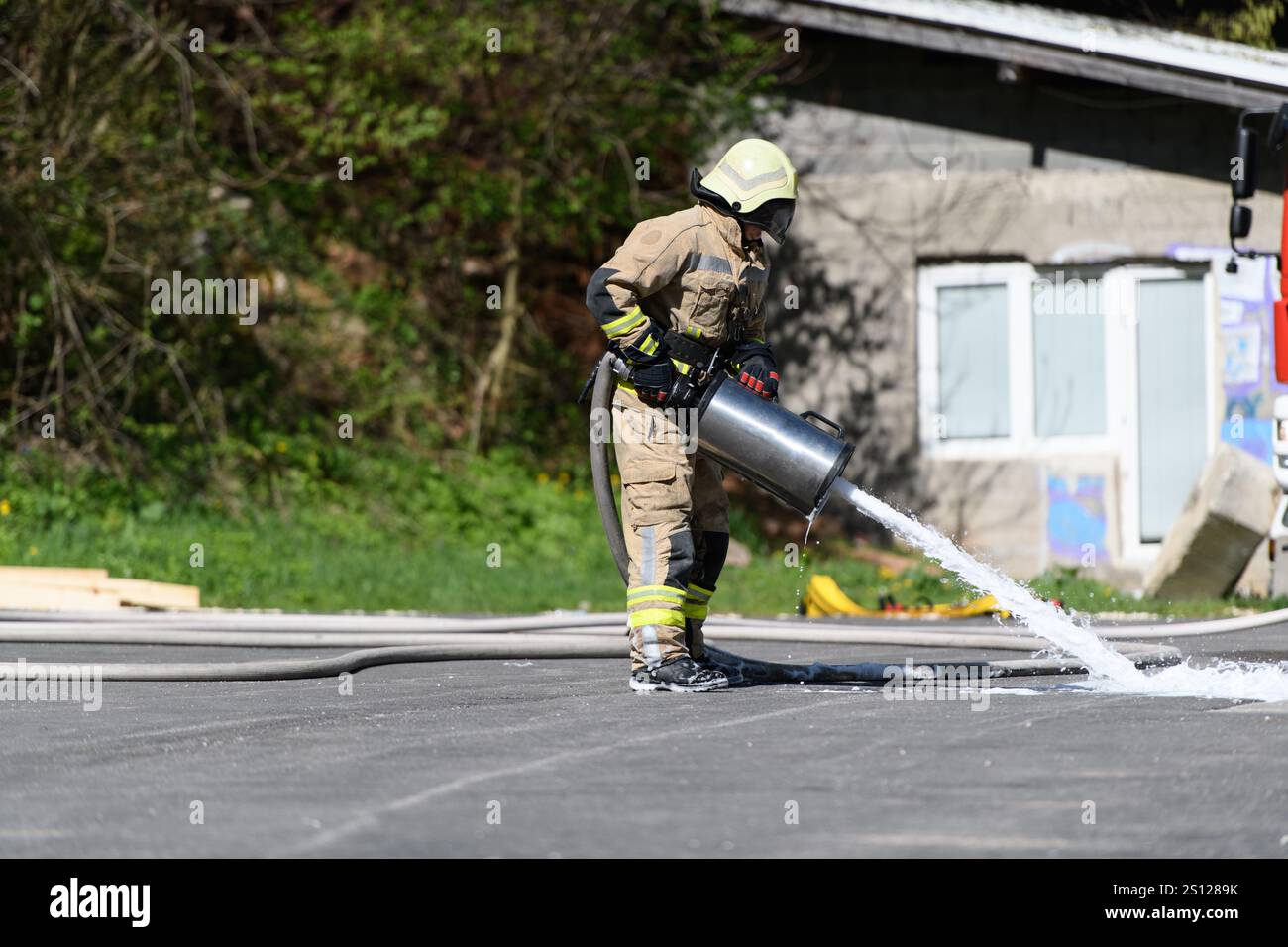 Firefighter using foam to extinguish fire on a melted oil can in a ...