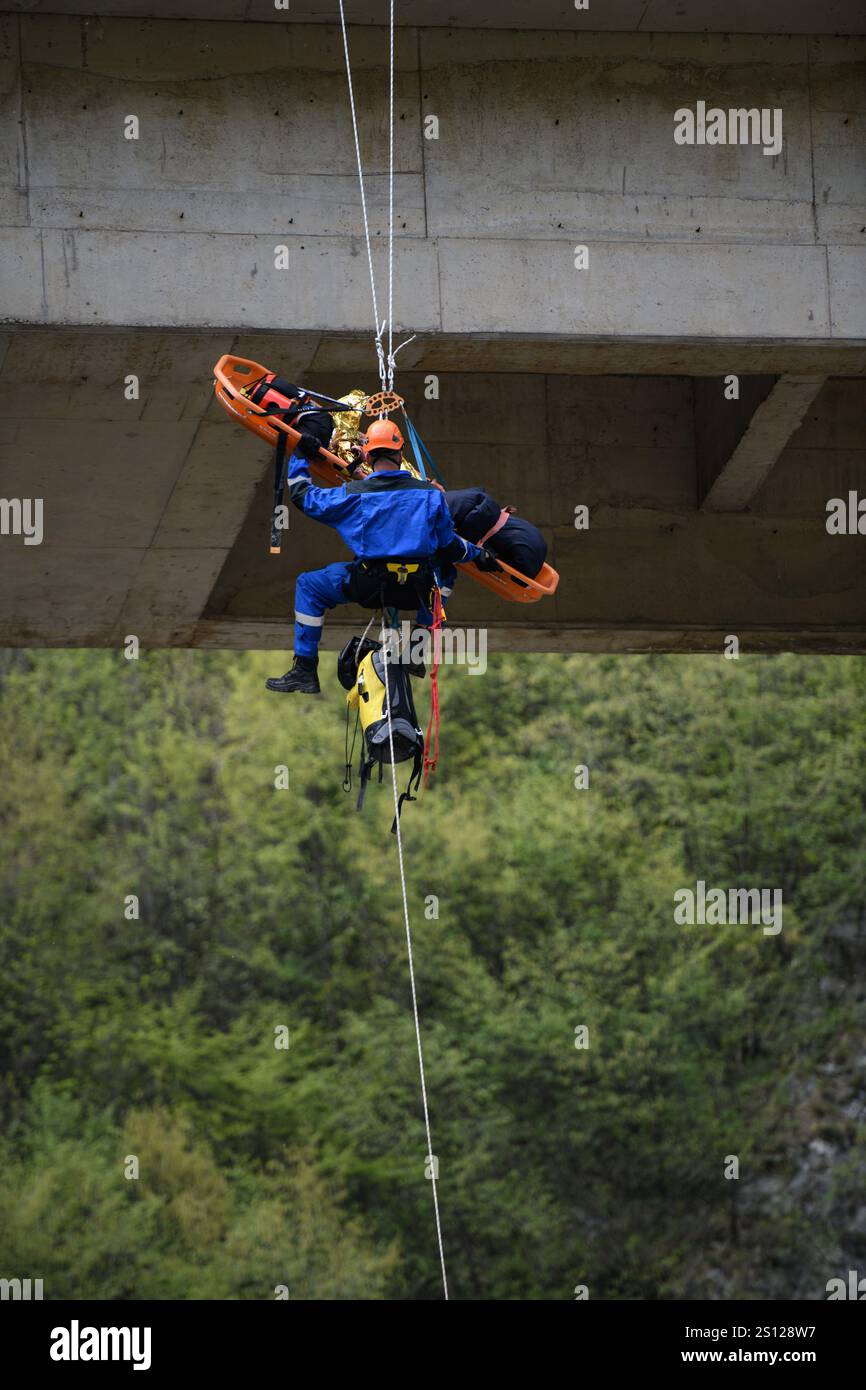 Professional rescuer performing bridge descent using rope system to ...