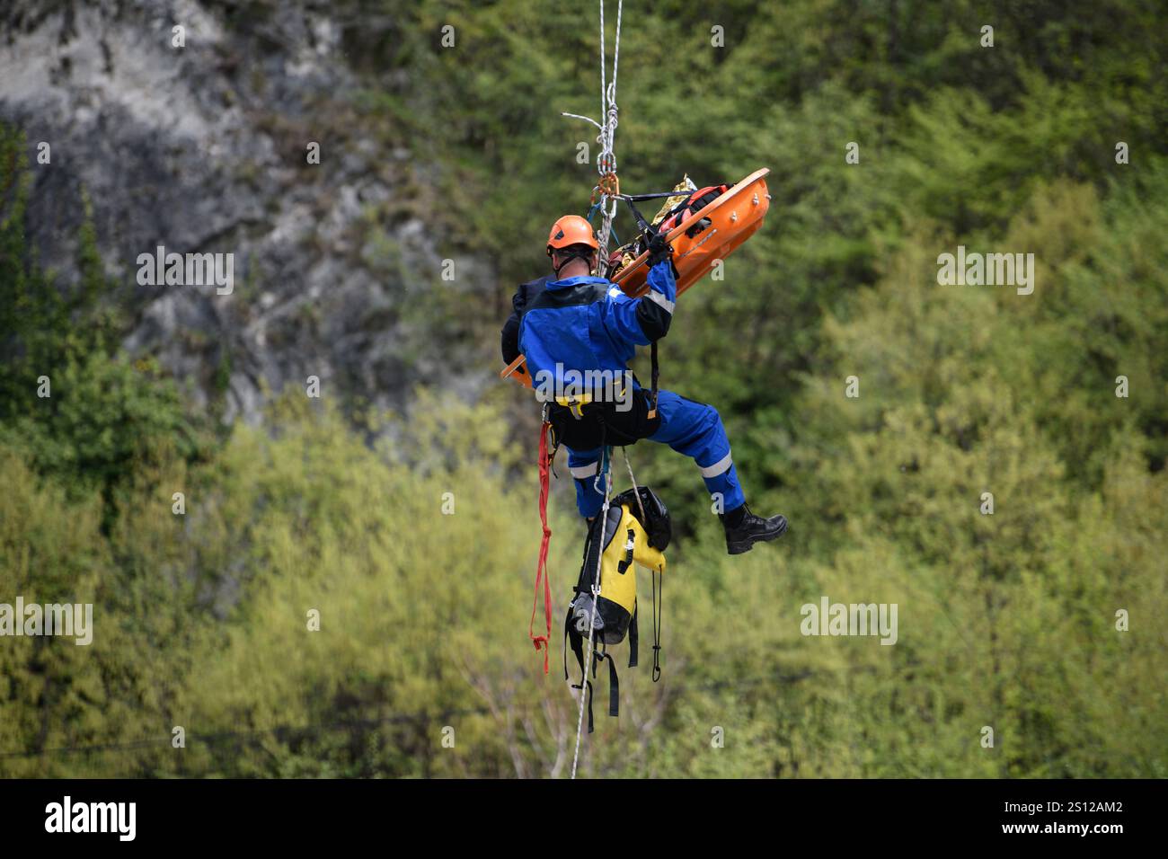 Professional rescuer performing bridge descent using rope system to ...