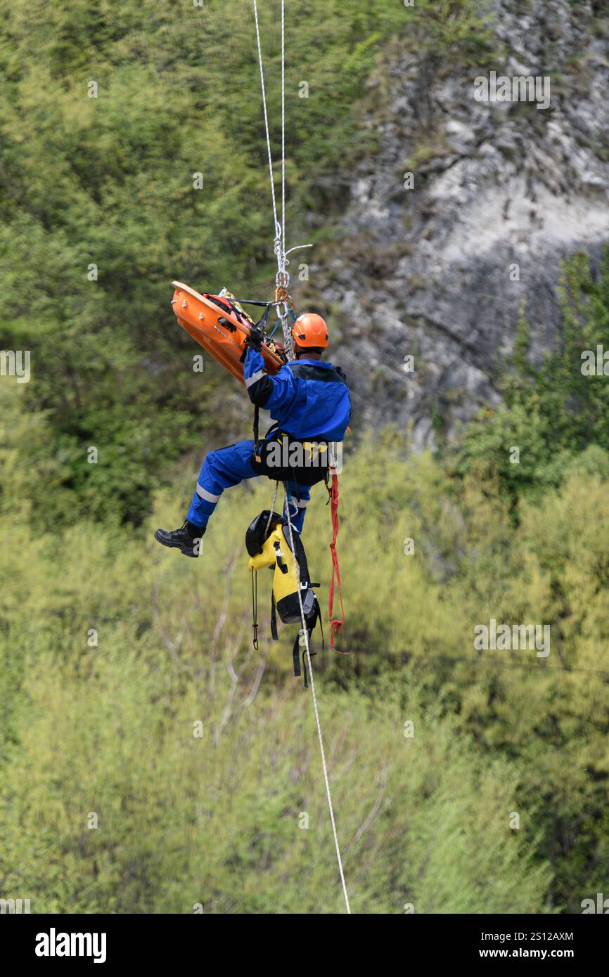 Rescuer with orange helmet and stretcher descending bridge for ...