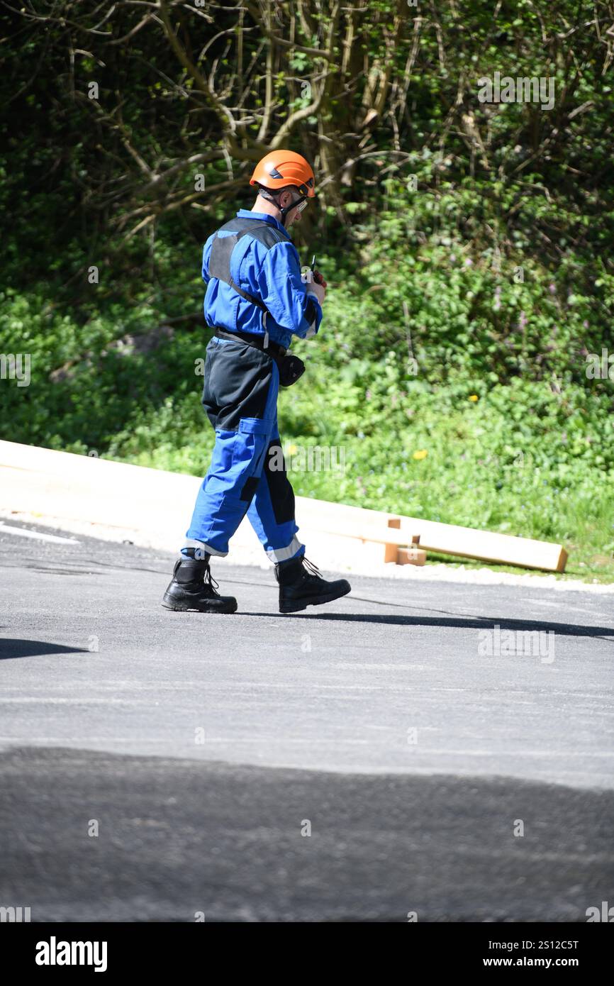 Rescuer in blue uniform and orange helmet walking outdoors planning ...