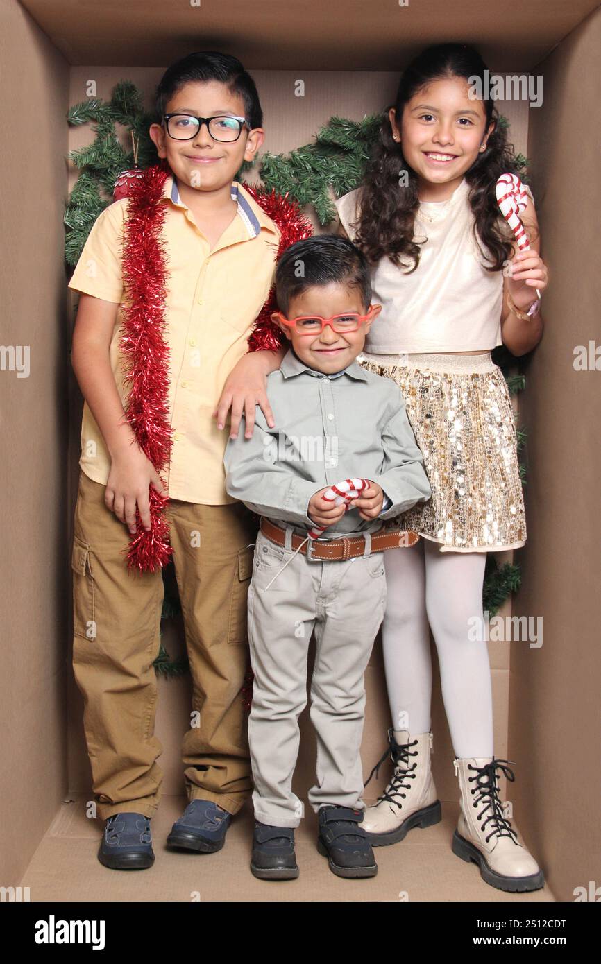 Two dark-skinned Latino brothers and sister inside a decorated ...