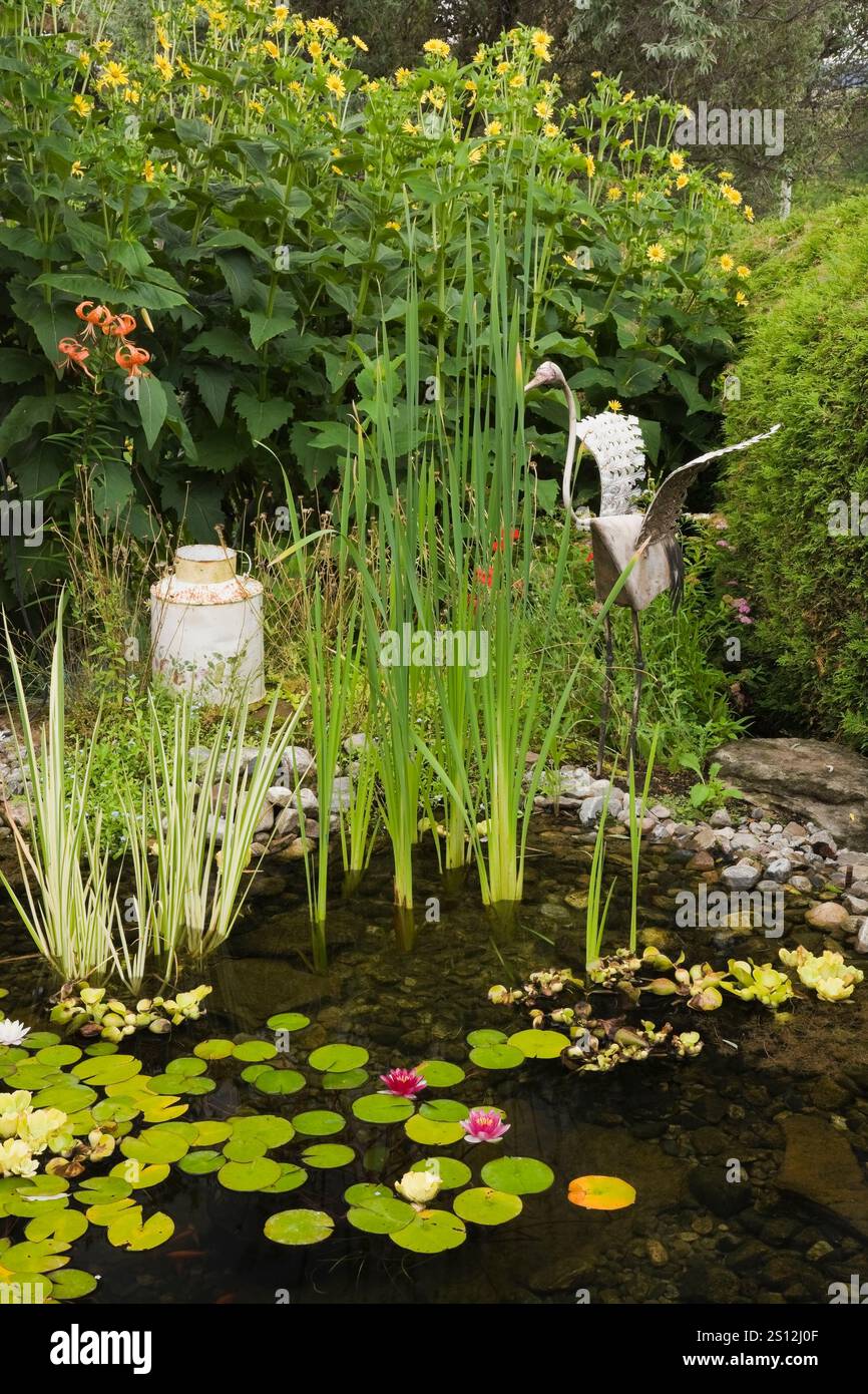 Old milk collecting bucket and metal bird sculpture on edge of pond ...