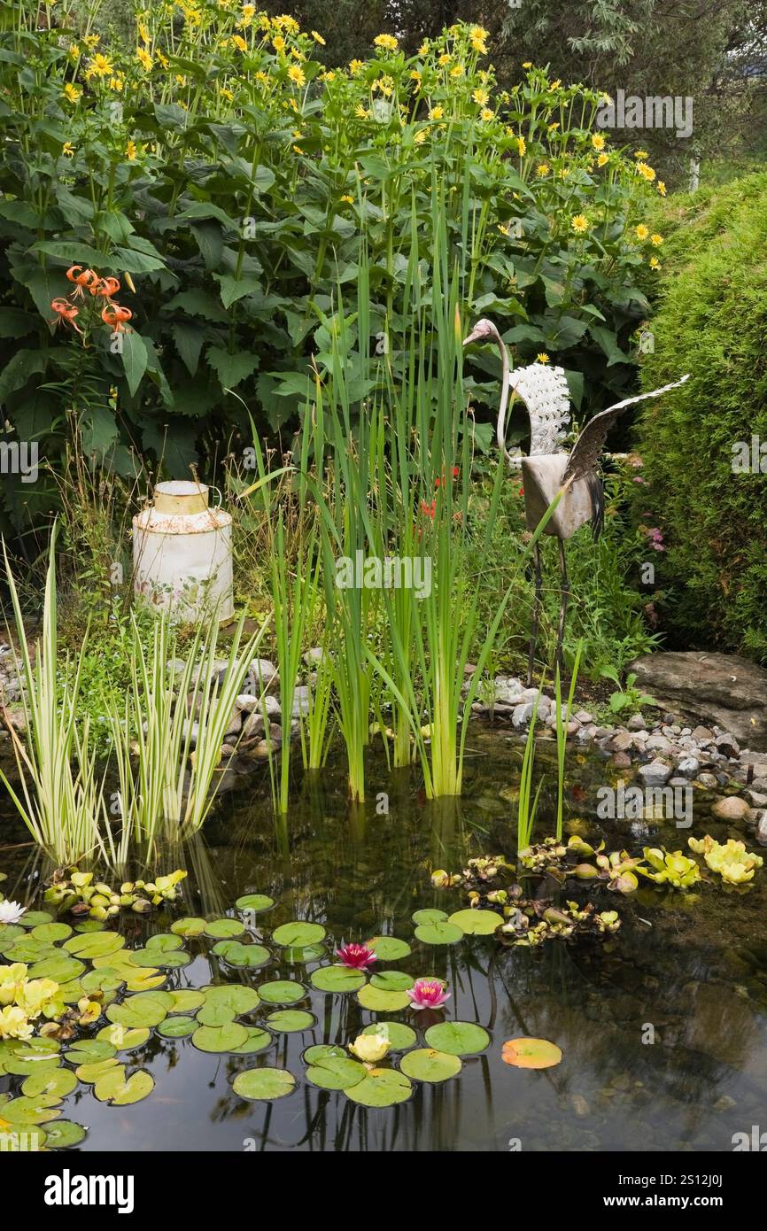 Old milk collecting bucket and metal bird sculpture on edge of pond ...