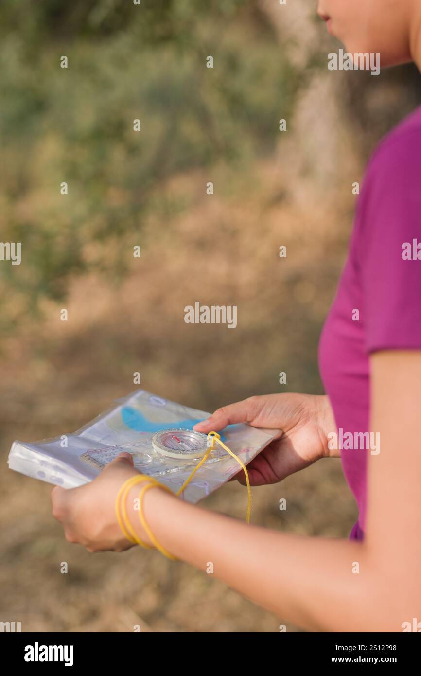 Young latin woman reading map and compass during orienteering race in ...