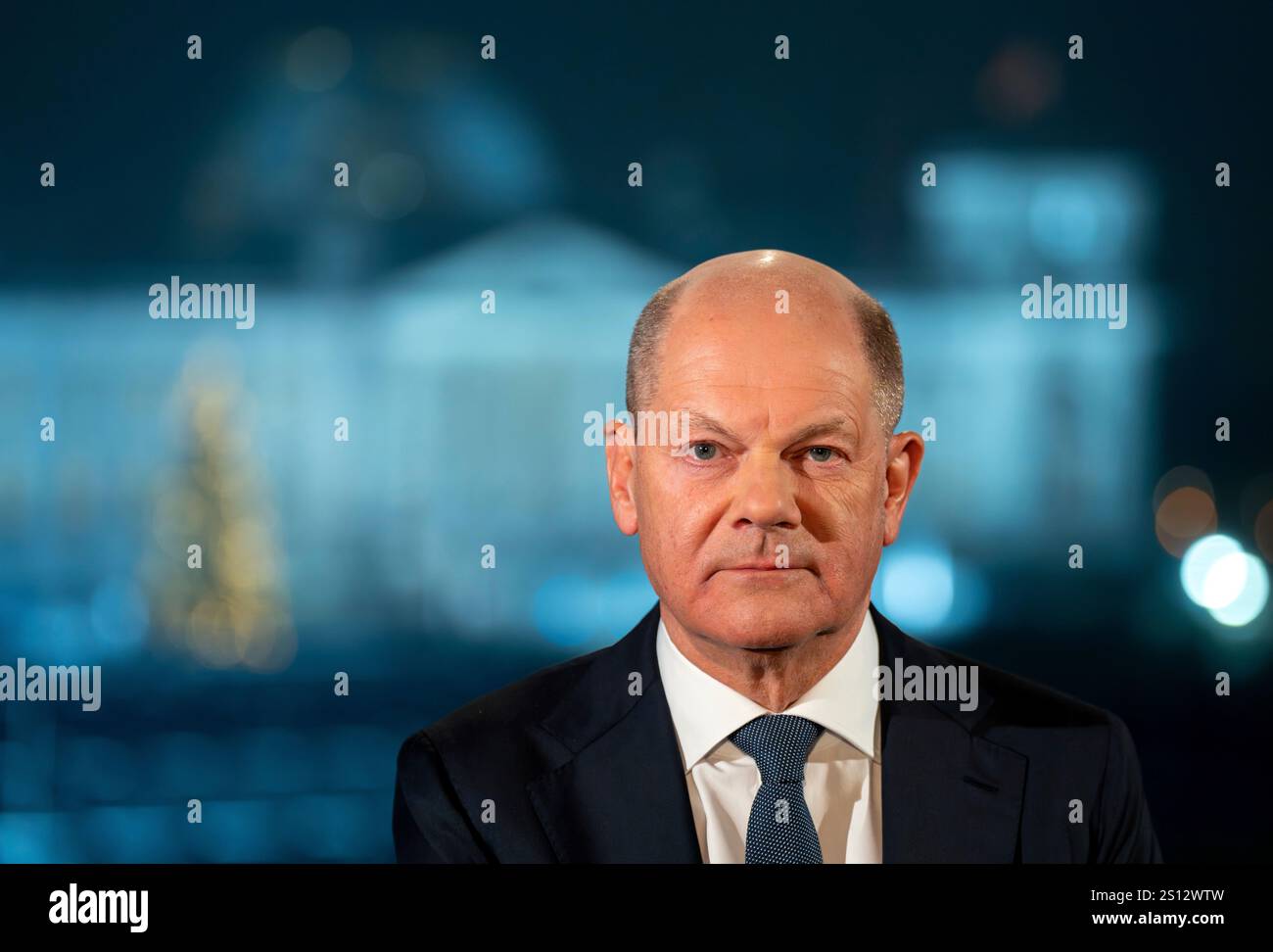 German Chancellor Olaf Scholz sits in front of the backdrop of the ...