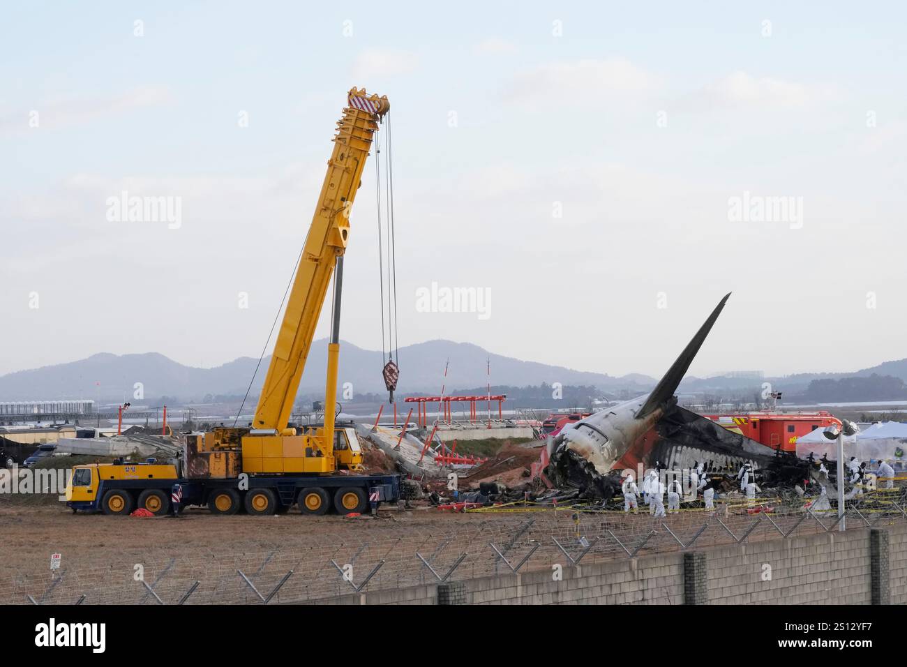 Rescue team members work at the site of a plane crash at Muan ...