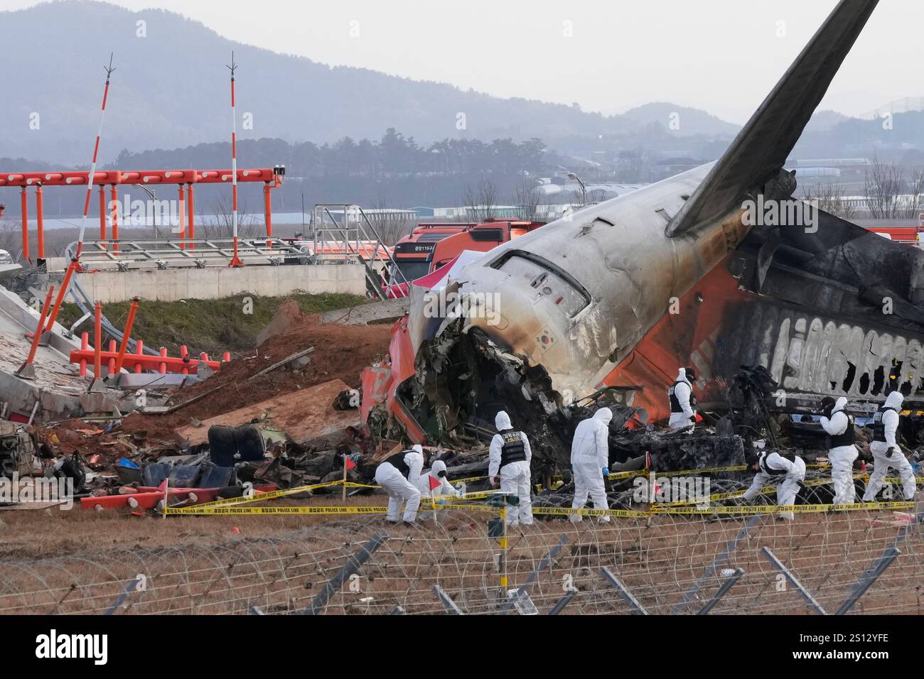 Rescue team members work at the site of a plane crash at Muan ...
