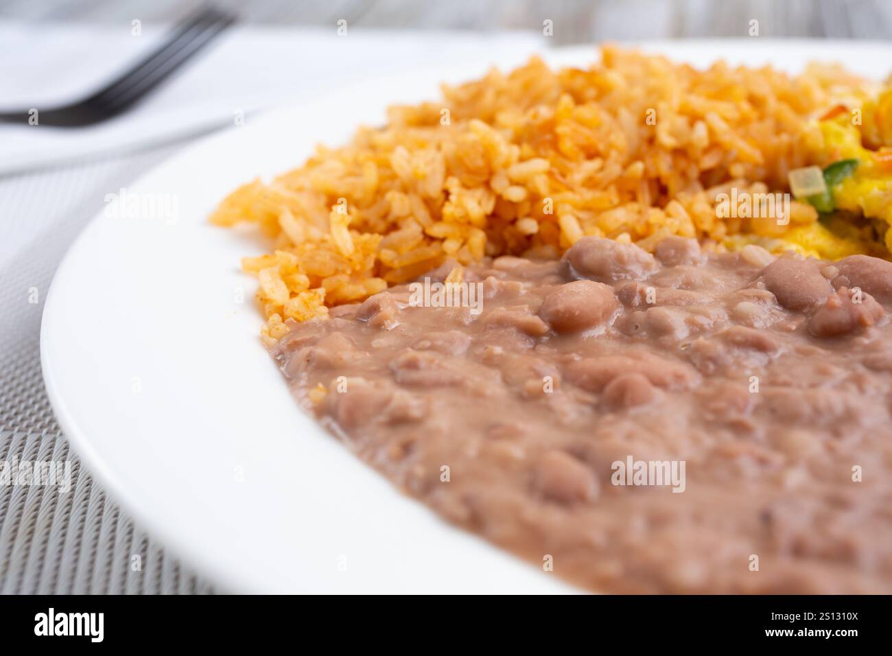 A closeup view of a plate featuring Mexican style rice and refried ...