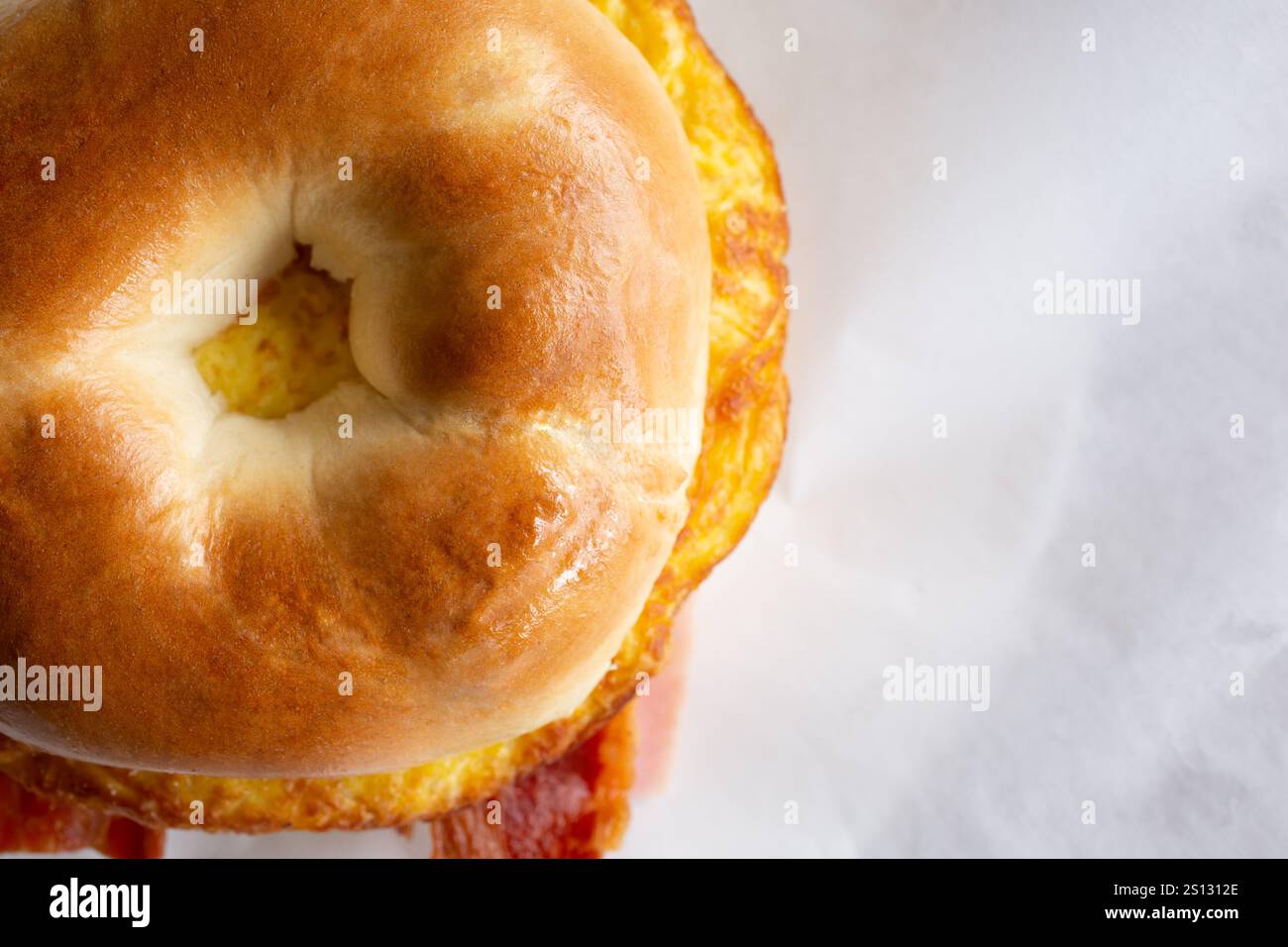 A top down view of a breakfast bagel sandwich, cut off on the left side ...