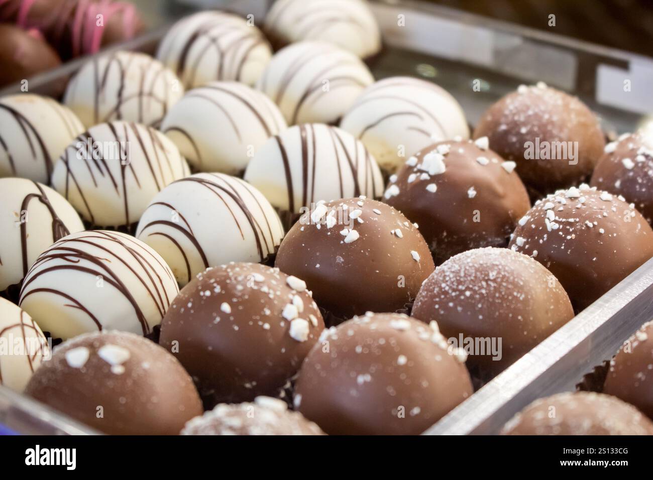 A closeup view of several chocolate truffle balls on display at a ...