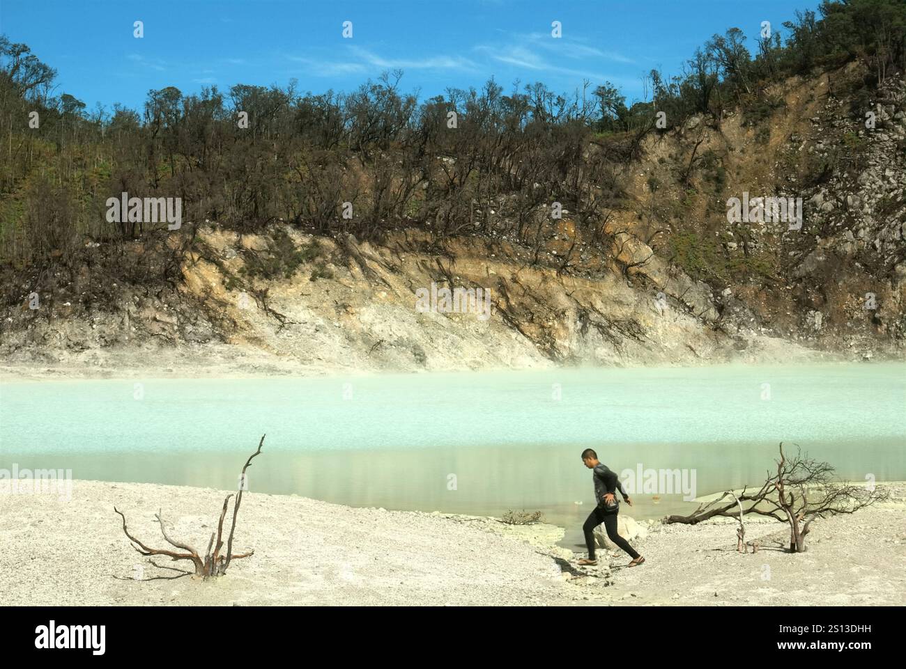 A man walking on sandy landscape on the crater of Mount Patuha, which ...