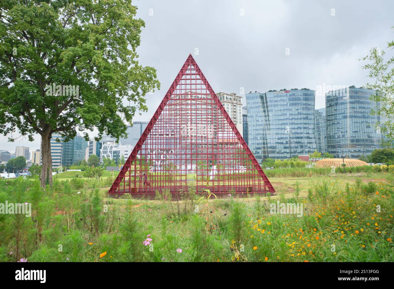 A large, red, steel triangle sculpture, statue in the park. At the ...